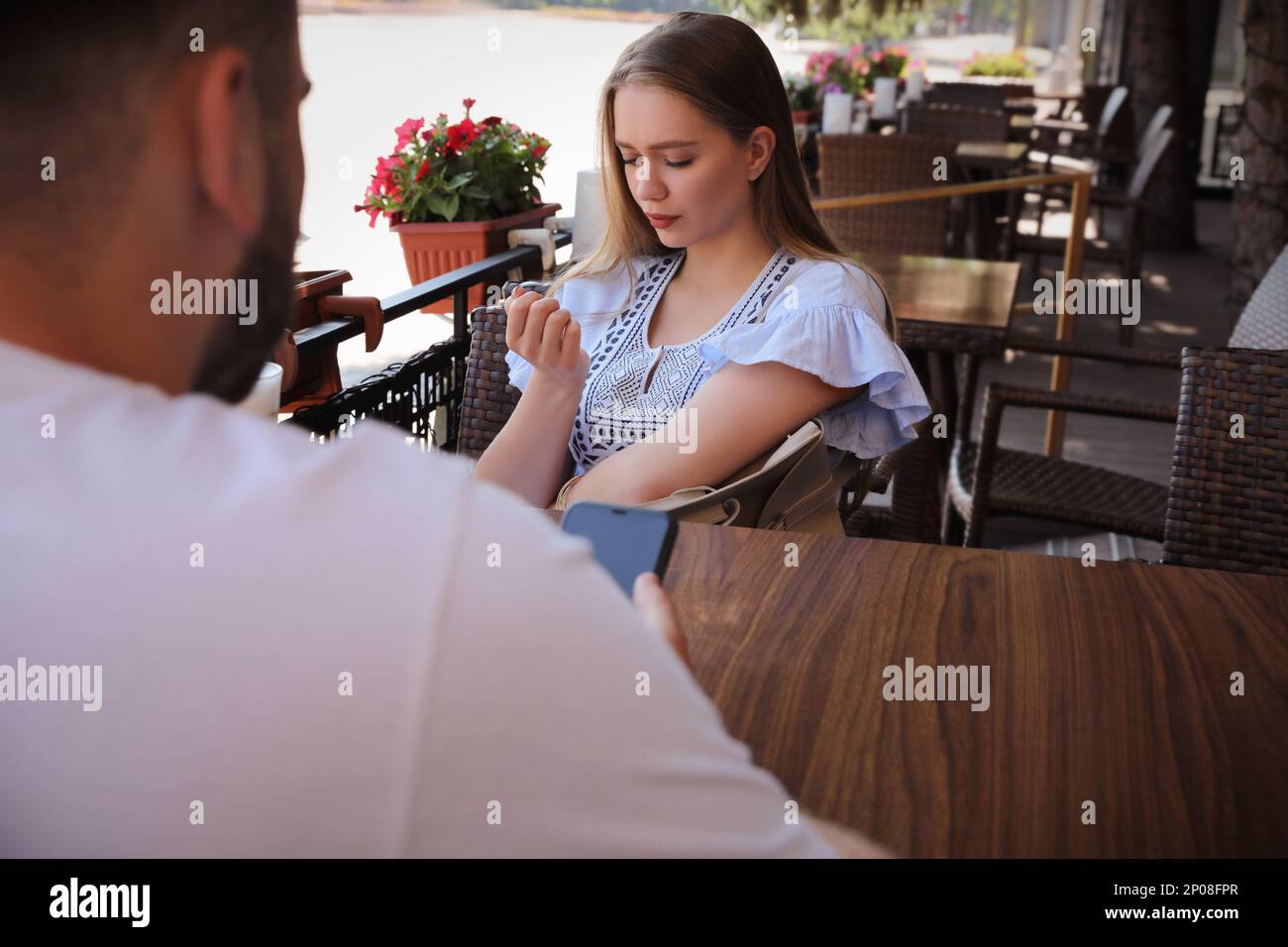 Young woman having boring date with guy in outdoor cafe Stock Photo - Alamy