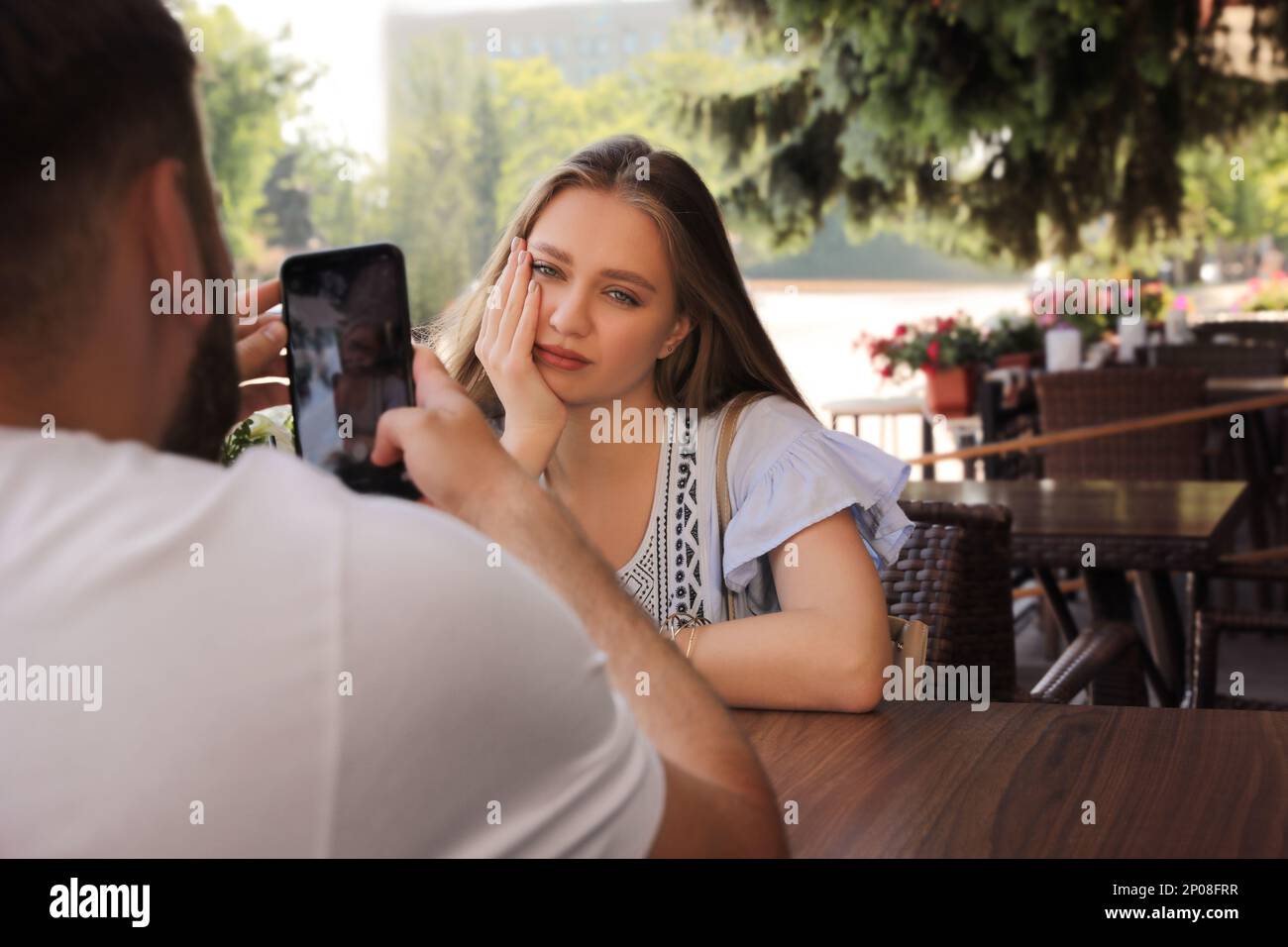 Young woman having boring date with guy in outdoor cafe Stock Photo - Alamy