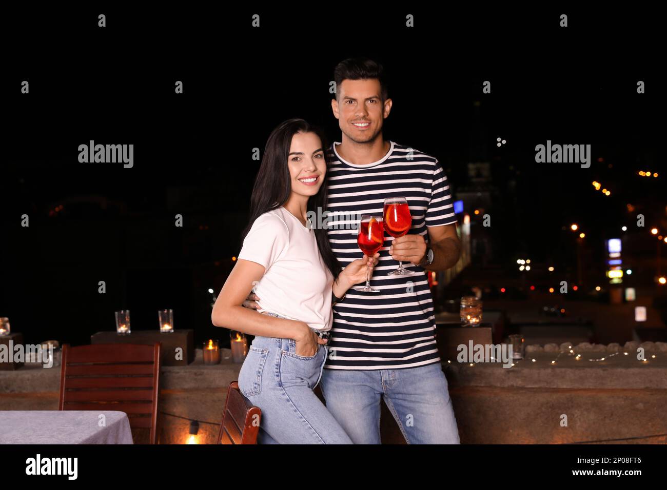 Romantic couple with glasses of cocktails on cafe terrace at night ...