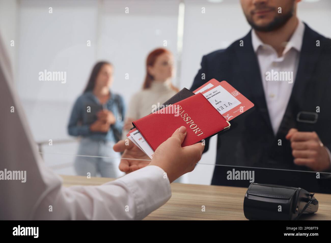 Agent giving passports with tickets to client at check-in desk in ...