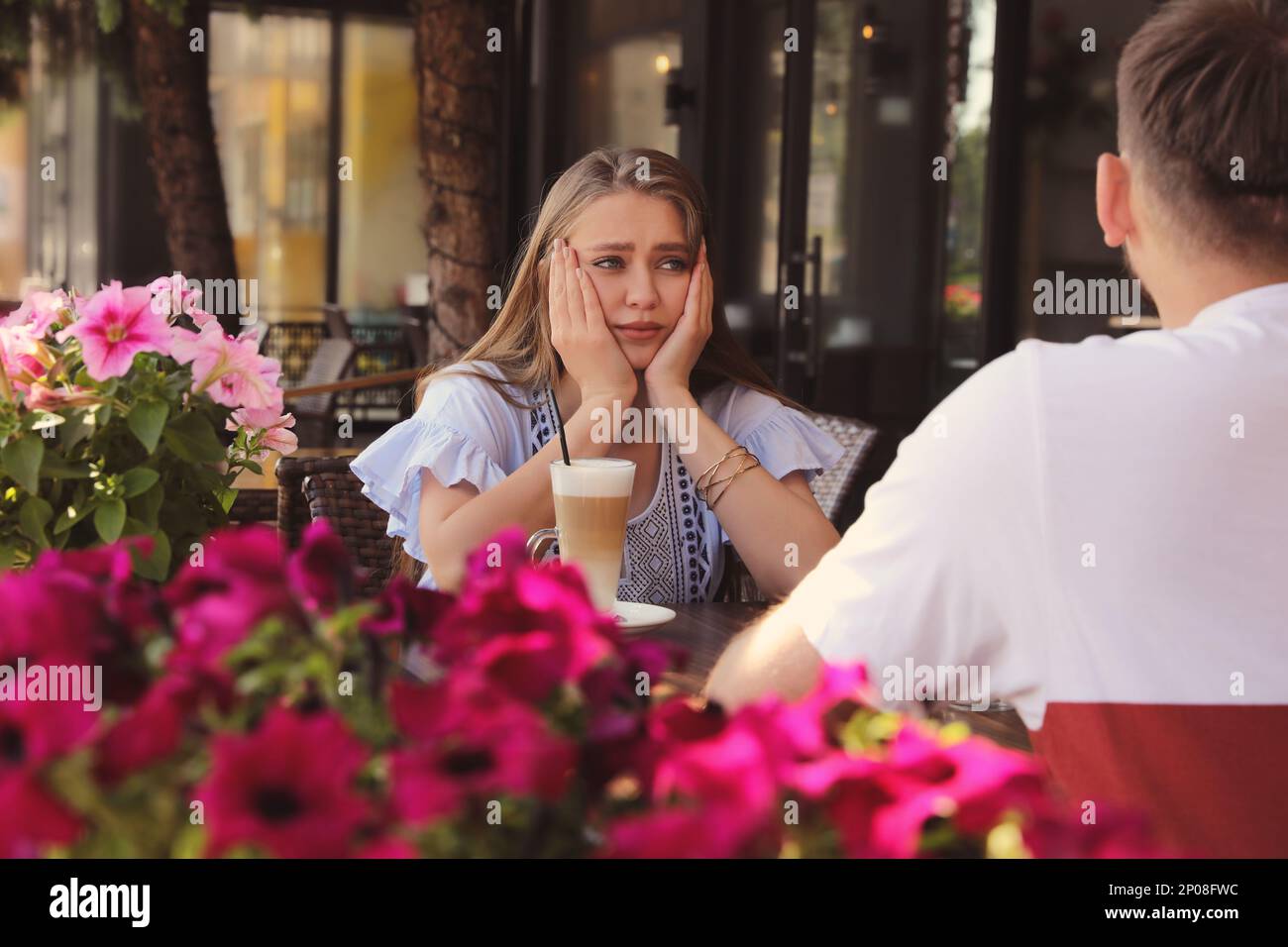 Young woman having boring date with guy in outdoor cafe Stock Photo - Alamy