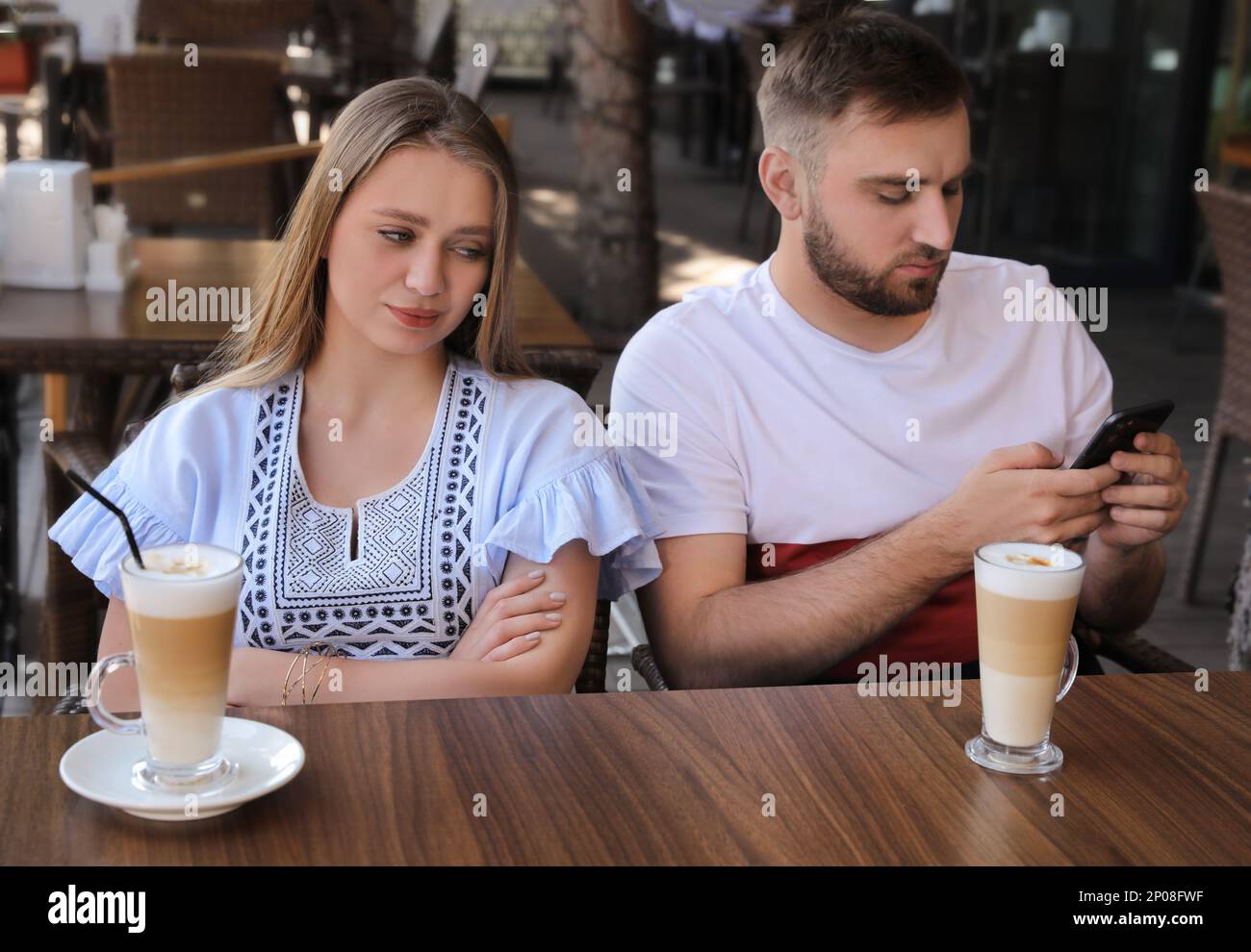 Young man with smartphone ignoring his girlfriend in outdoor cafe. Boring date Stock Photo - Alamy