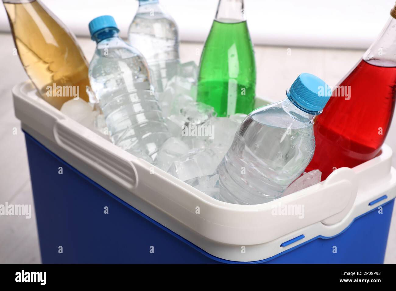 Blue plastic cool box with ice cubes and refreshing drinks, closeup ...