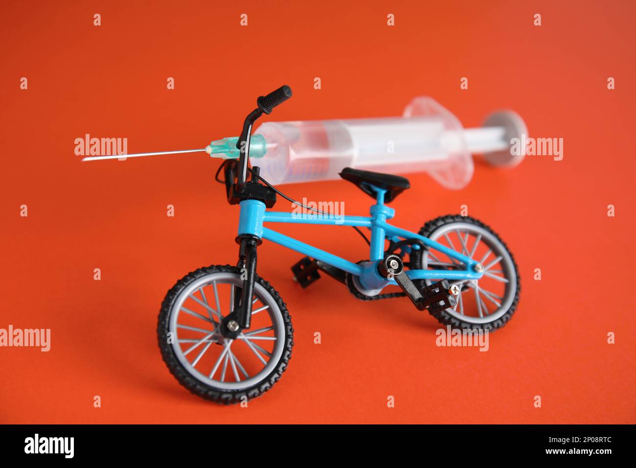Bike model and syringe on red background. Using doping in cycling sport ...