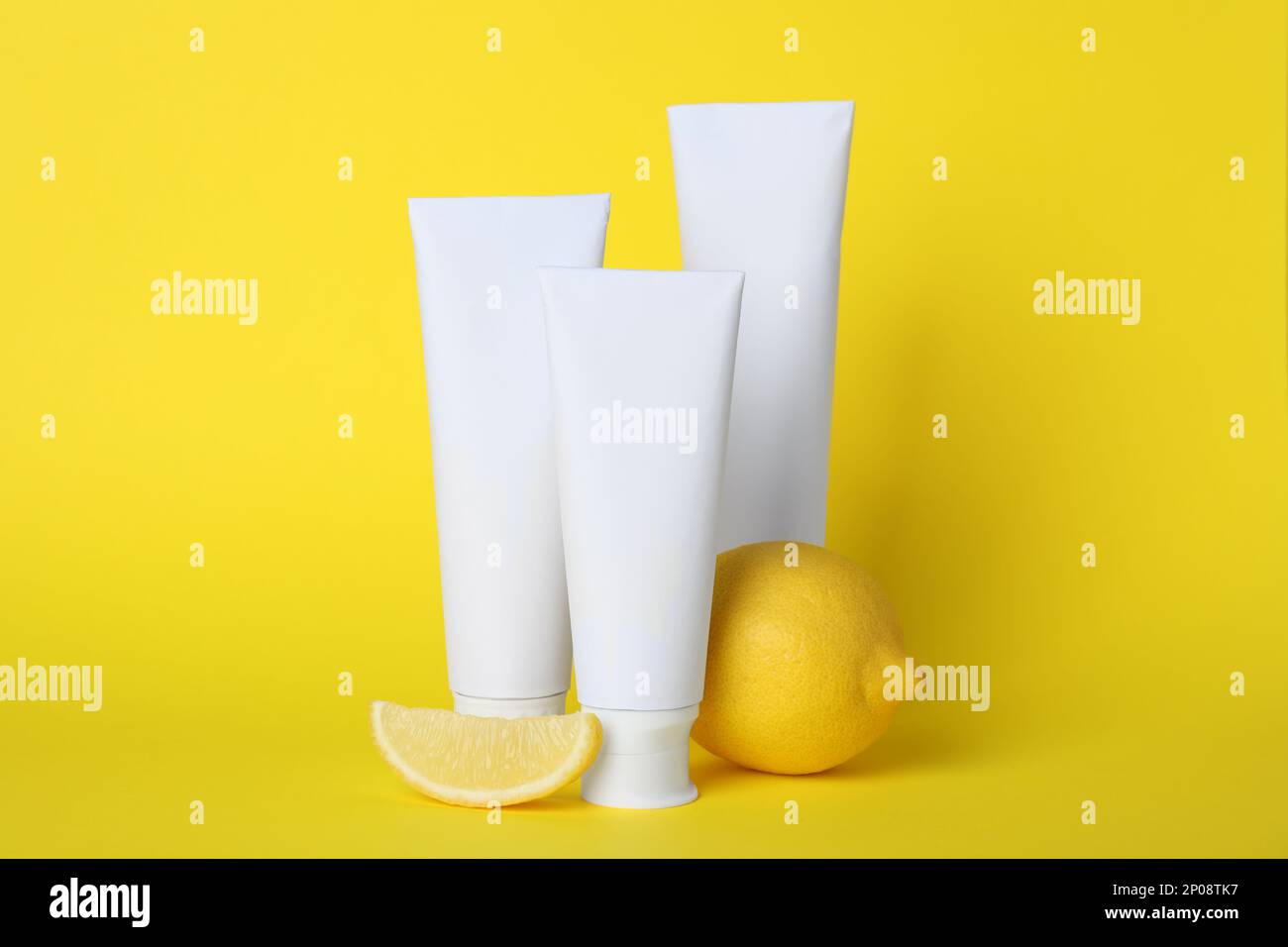 Blank tubes of toothpaste and fresh lemon on yellow background Stock ...