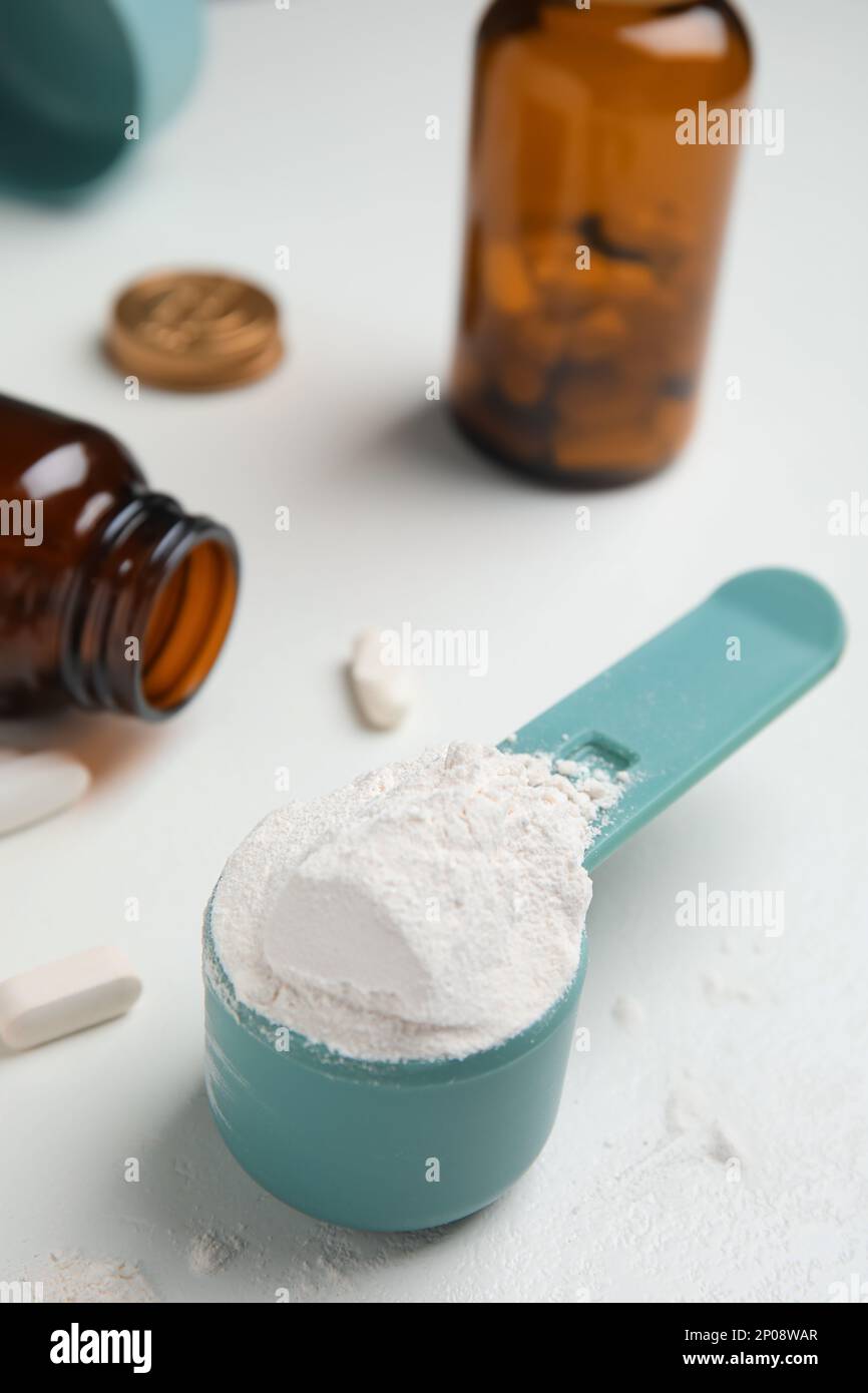 Measuring scoop of amino acids powder on white table Stock Photo - Alamy