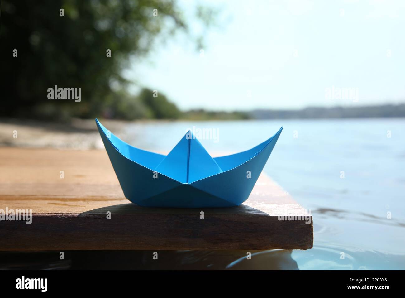 Light blue paper boat on wooden pier near river Stock Photo - Alamy