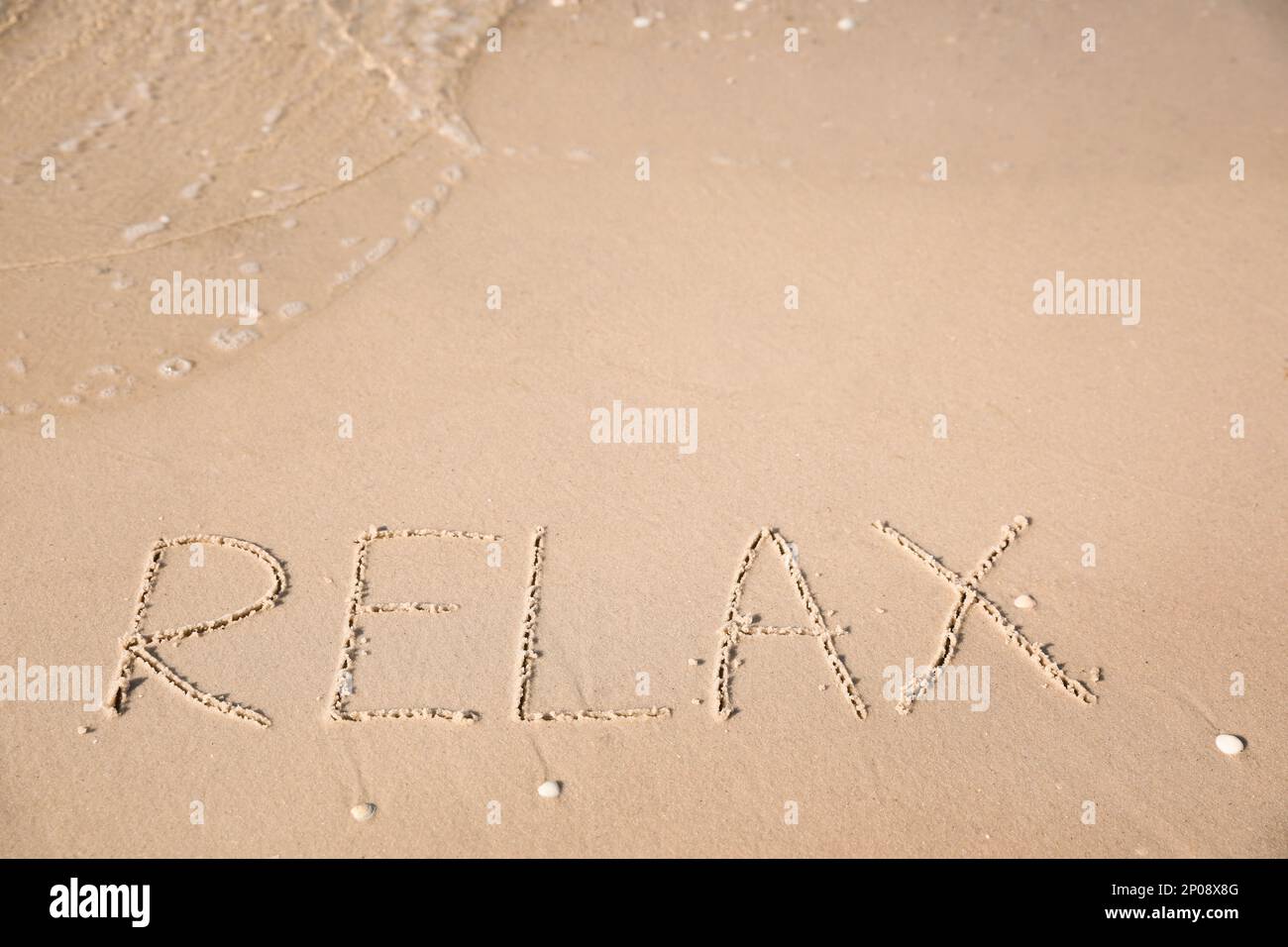 Word Relax written on sand at beach Stock Photo - Alamy