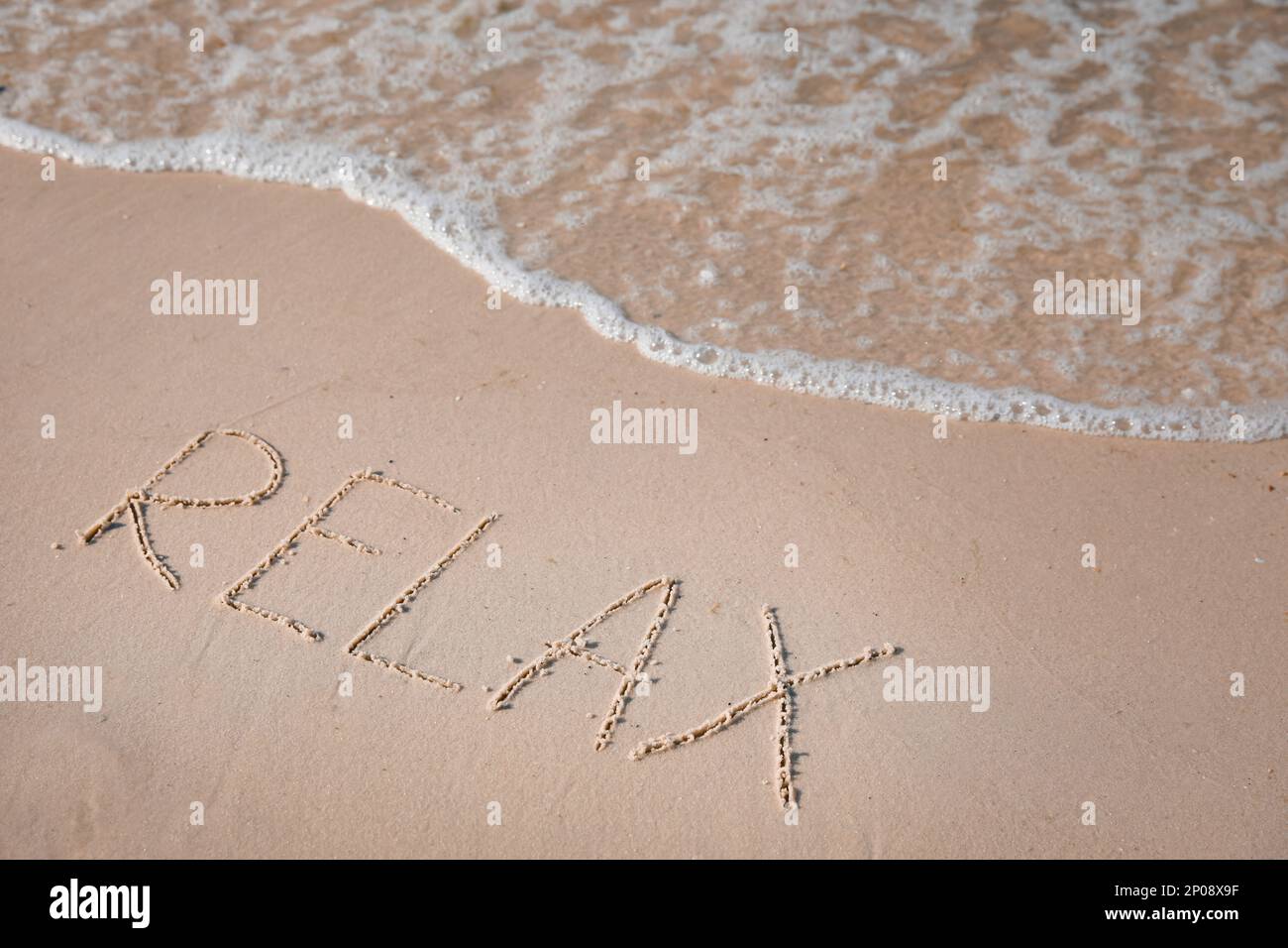 Word Relax written on sand at beach Stock Photo - Alamy