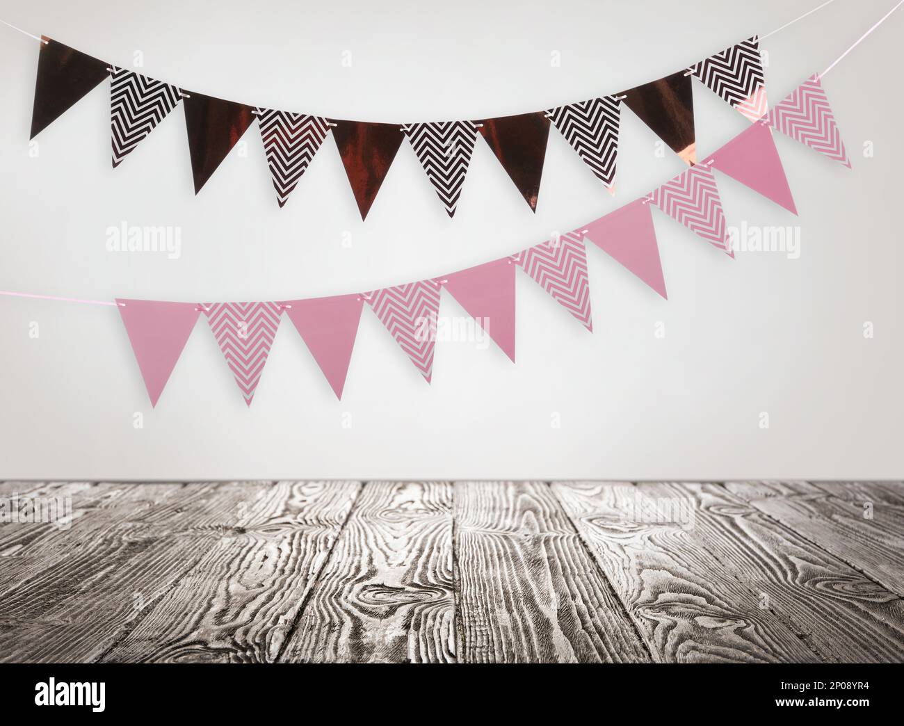Empty wooden table and decorative bunting flags hanging on white wall ...