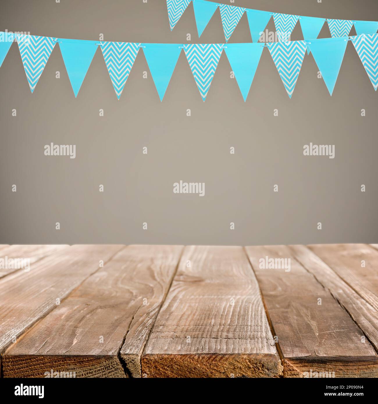 Empty wooden table and decorative bunting flags hanging on beige wall ...