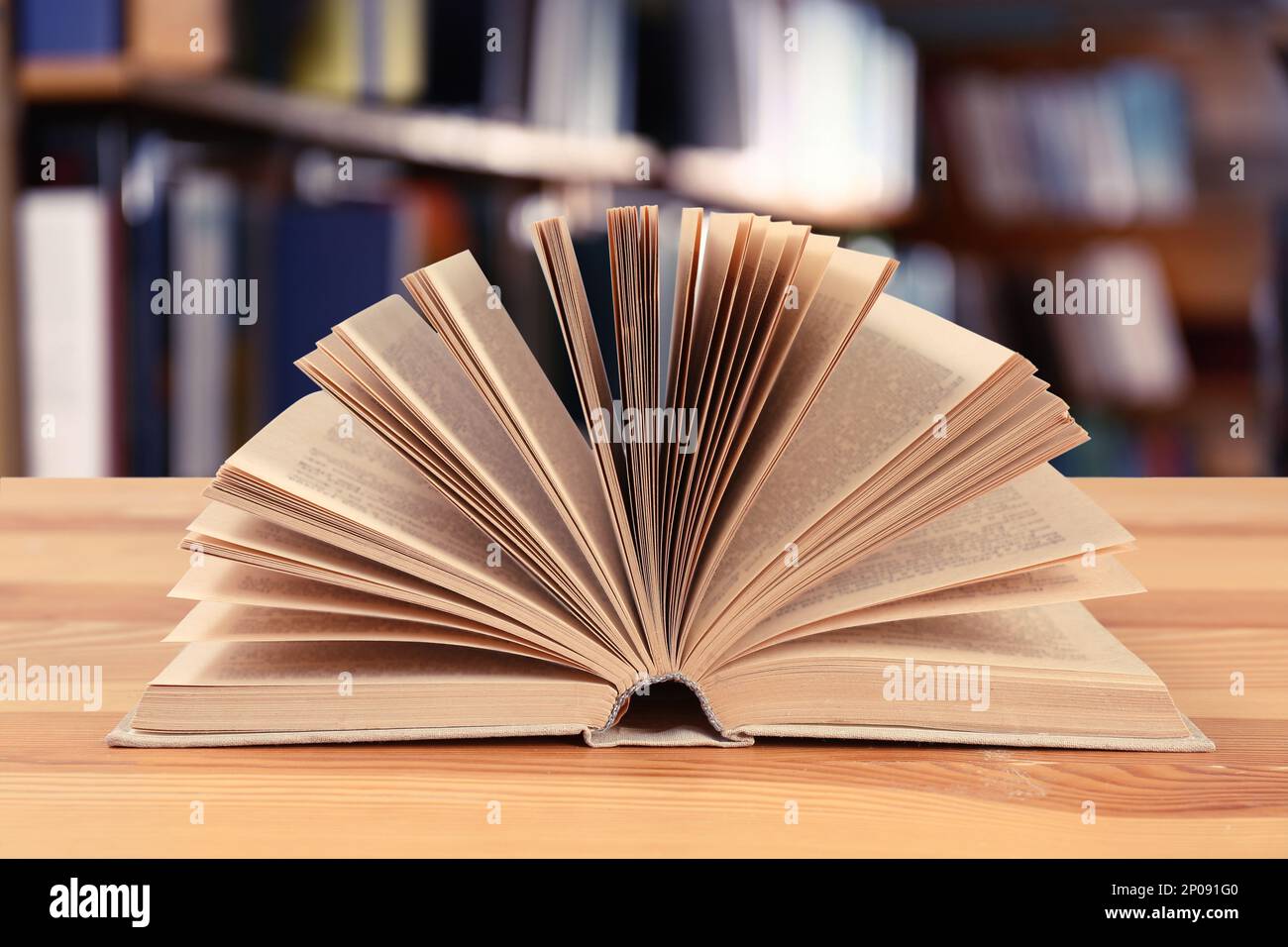 Open book on wooden table in library Stock Photo - Alamy