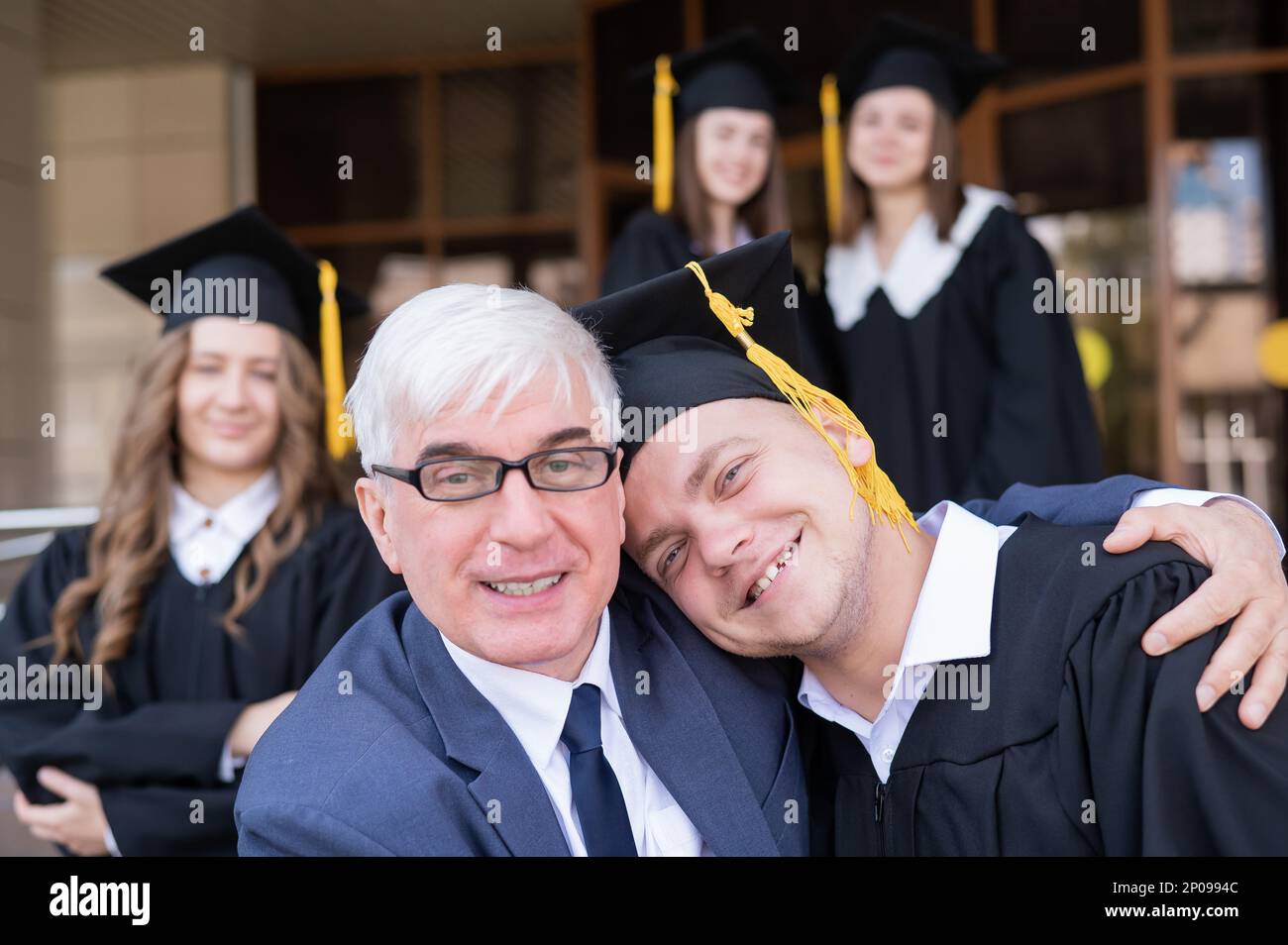 Father and son embrace at graduation. Parent congratulates university ...