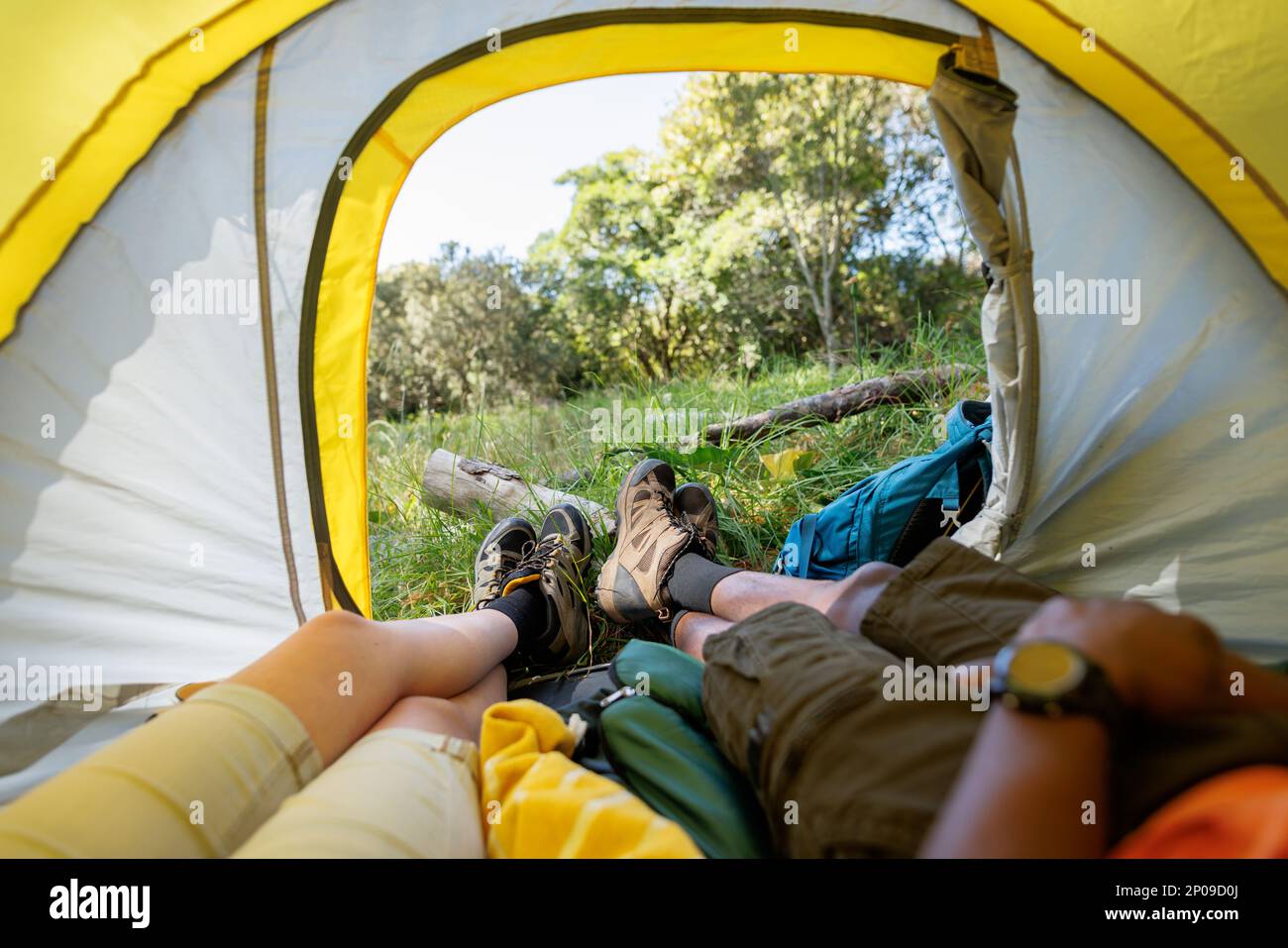 View from in tent of legs of diverse couple camping, lying in tent ...