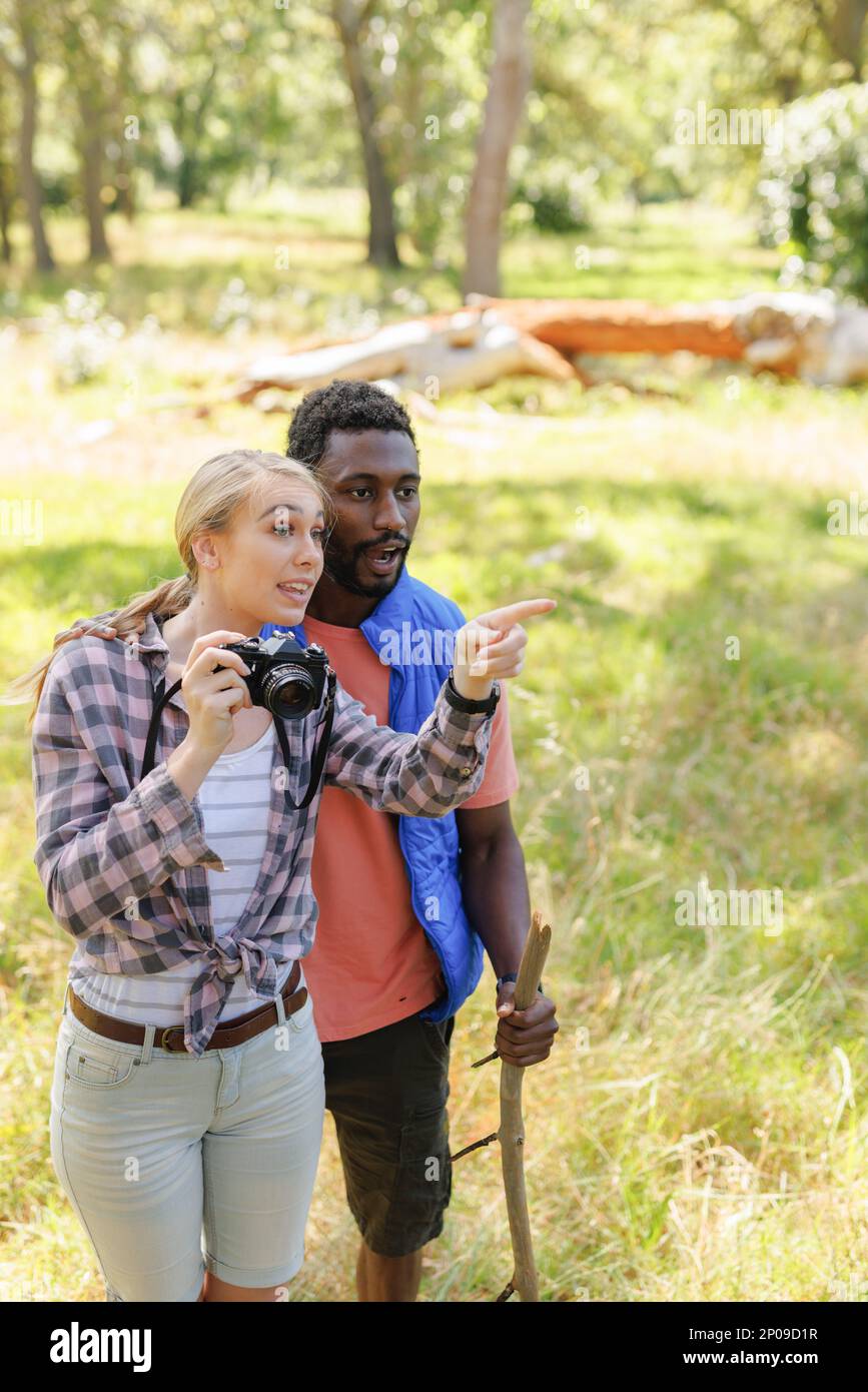 Vertical of excited diverse couple trekking in countryside, stopping to ...