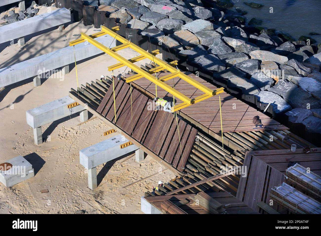 Crews load a section of pre-built boardwalk onto the concrete pilings ...