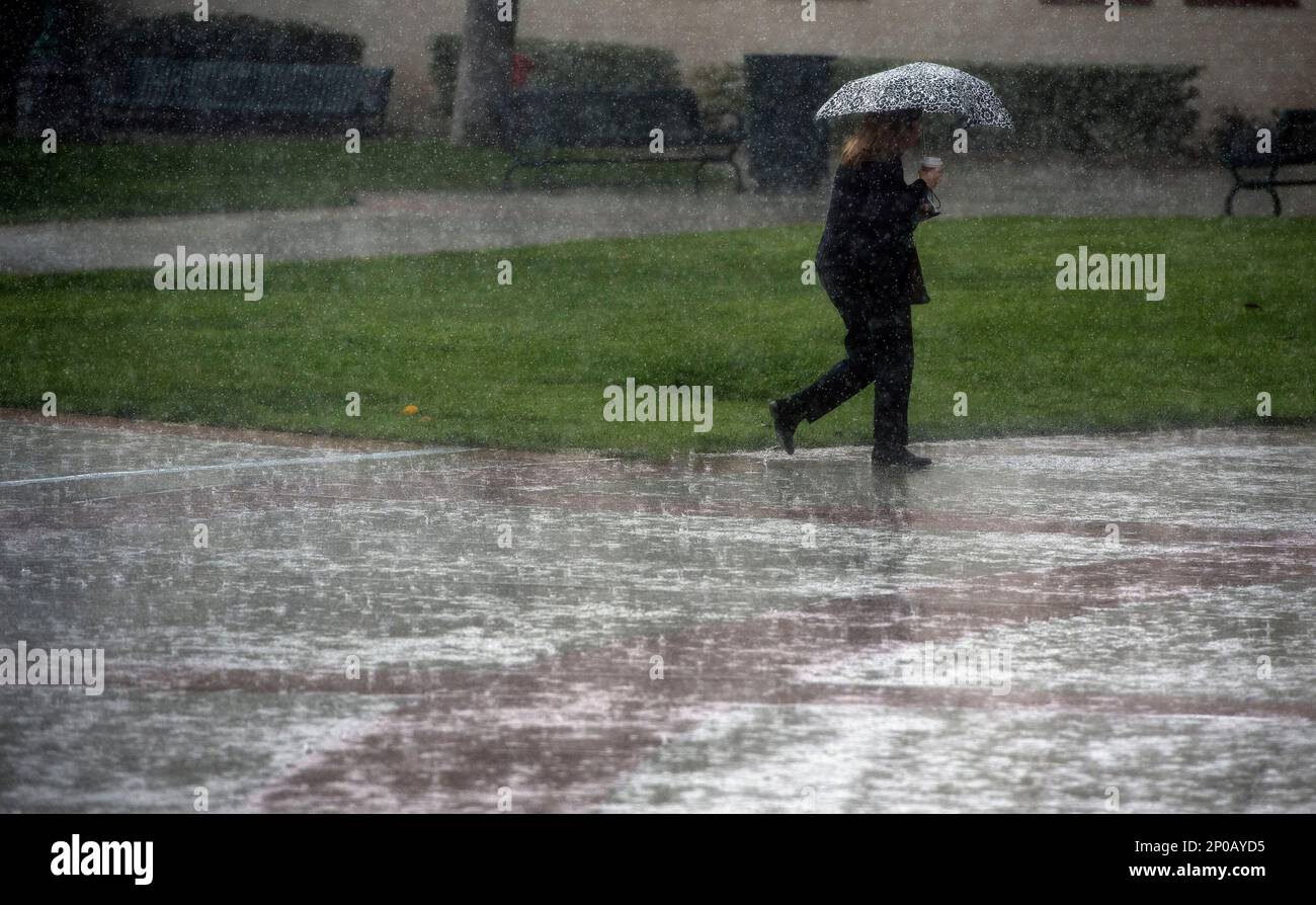 A pedestrian gets pummeled with rain and hail during a cloud burst in ...