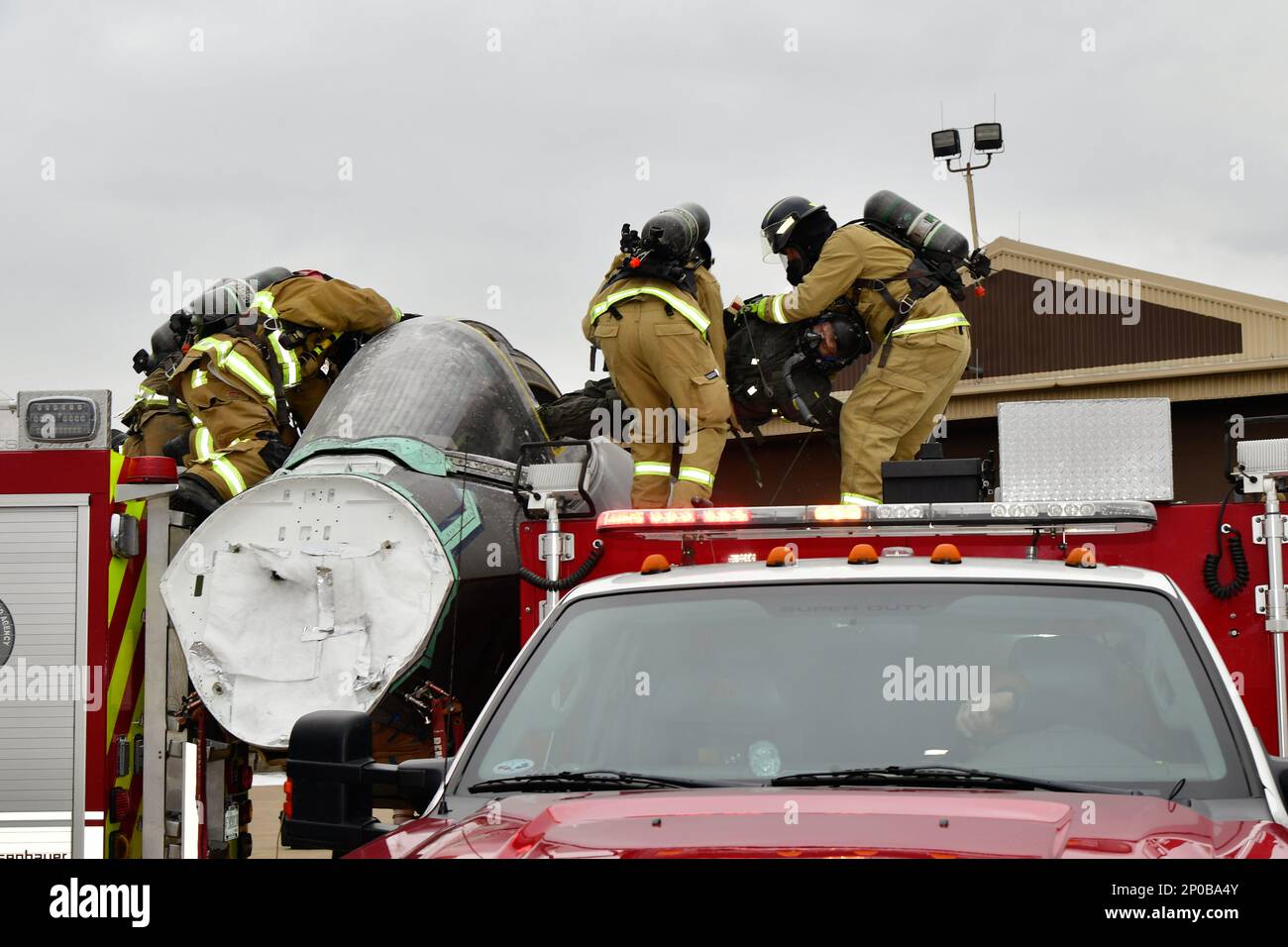 Air Force firefighters use fire trucks to shield aircraft inlets, while ...