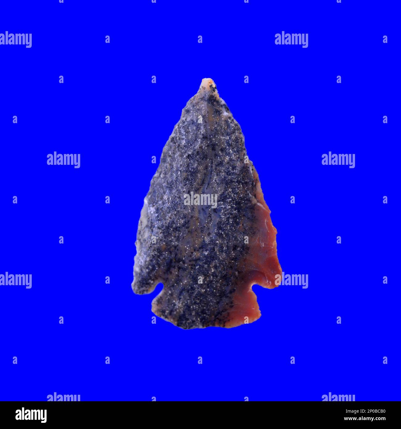 Ancient Prehistoric primitive stone arrowhead isolated over blue Stock ...