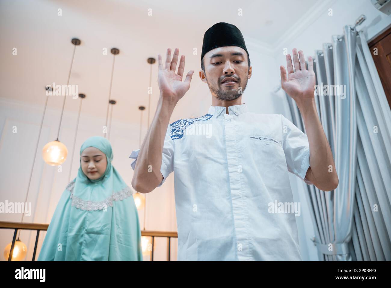 Asian Muslim man leads prayers with woman saying Allahu Akbar Stock ...