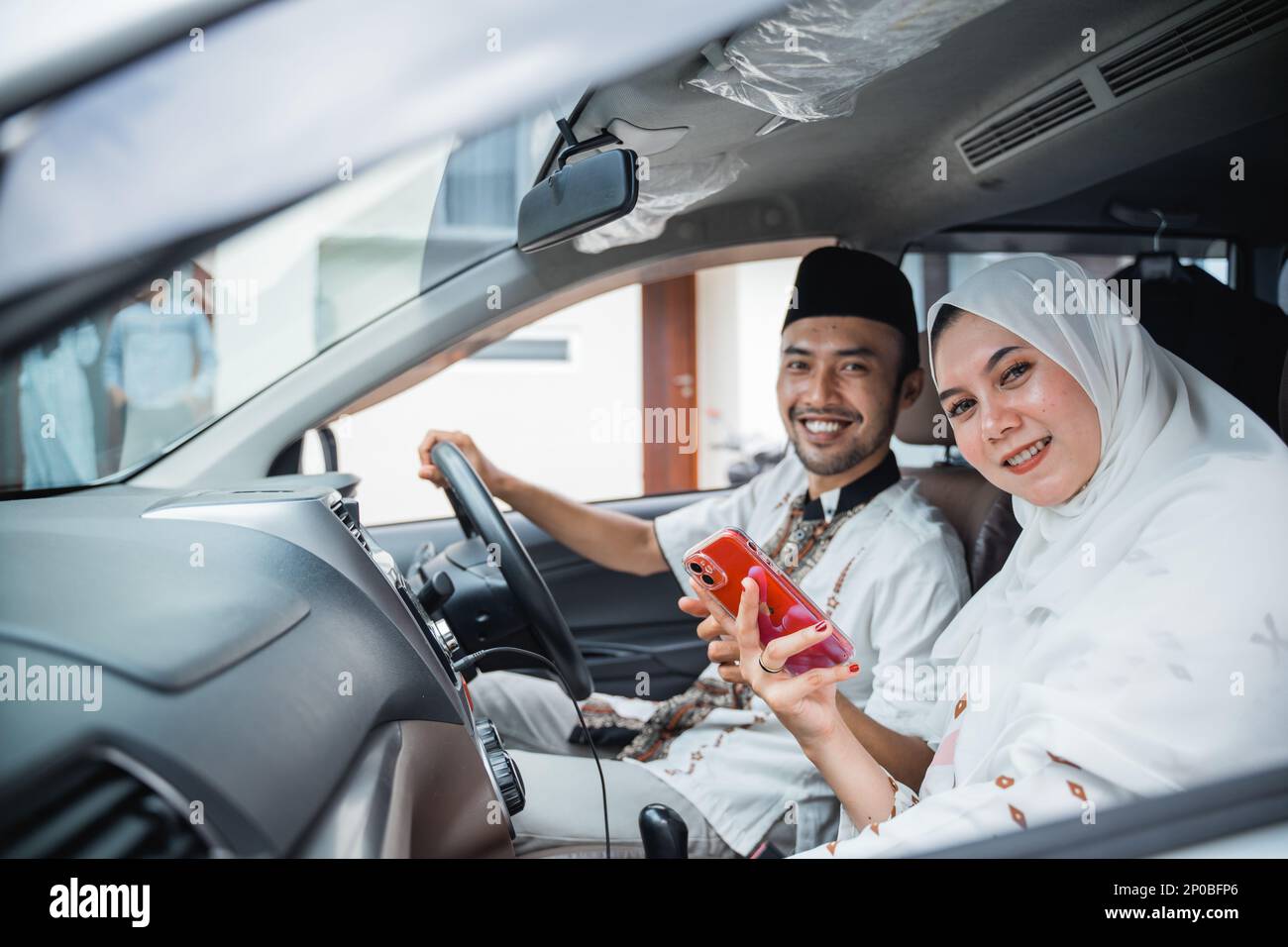 Asian Muslim husband and wife using cell phone in car Stock Photo - Alamy