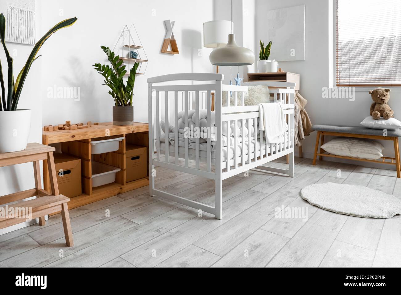 Interior of light children's bedroom with baby crib, table and bench ...