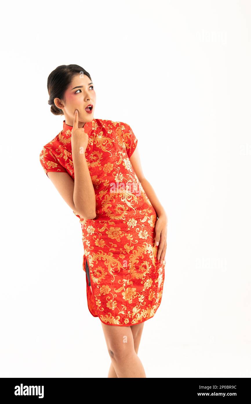 curious asian woman in red cheongsam standing and pointing at her cheek ...