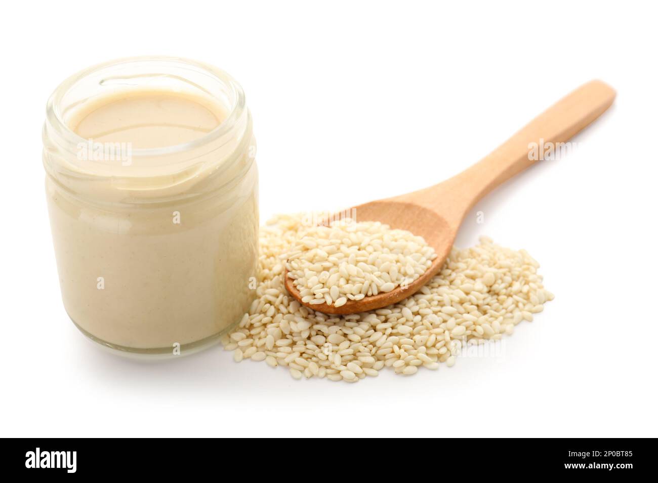 Glass jar od tasty tahini and spoon with sesame seeds on white ...