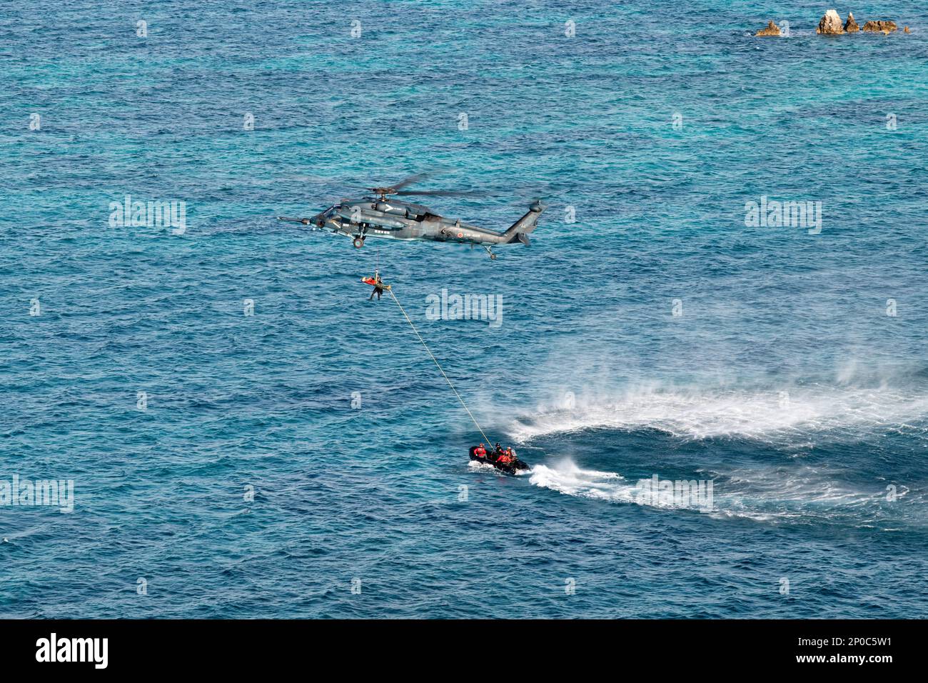 A Japanese Air Self-Defense Force UH-60J helicopter hoists a basket ...