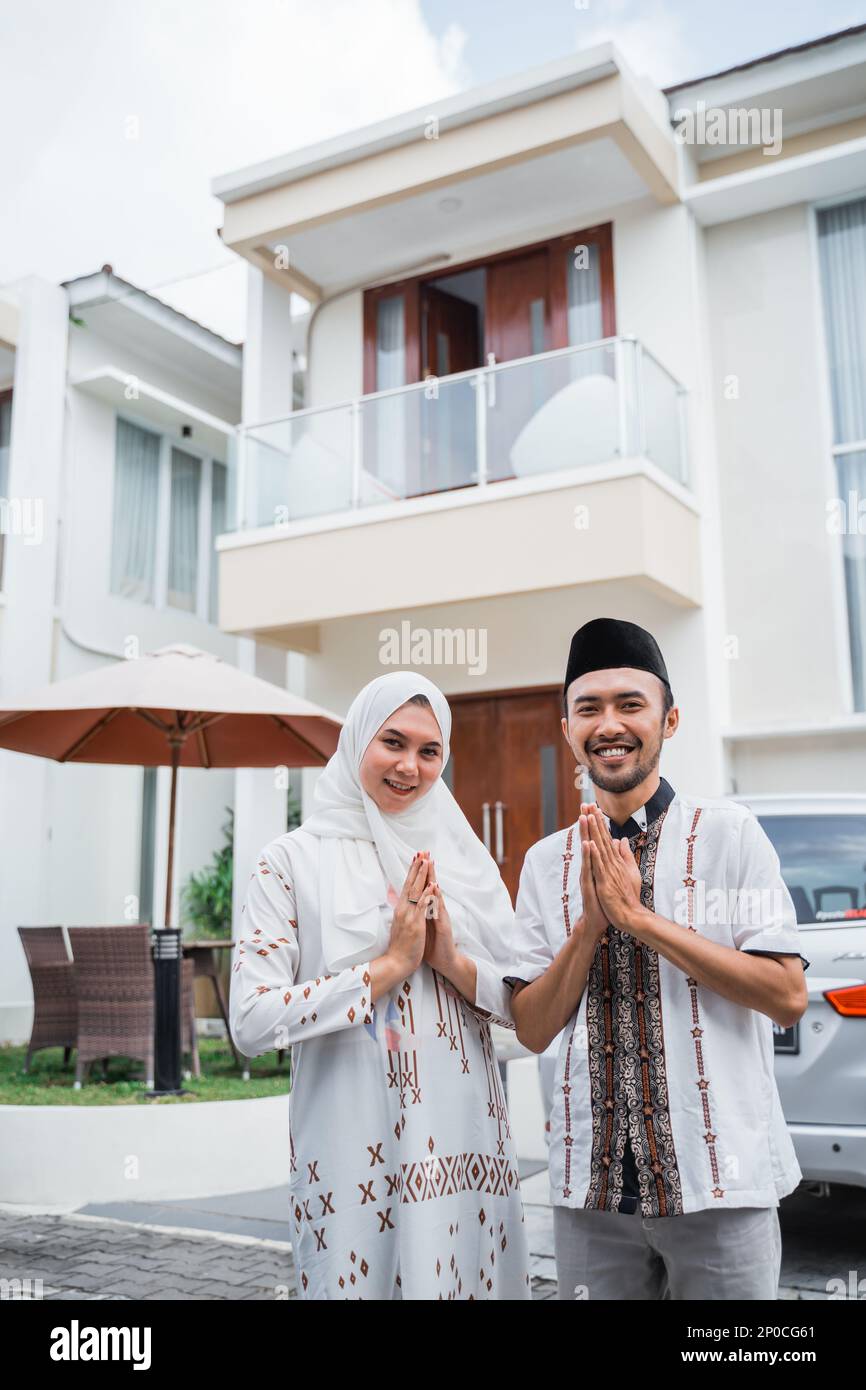 Asian Muslim couple smiles with a welcome hand gesture Stock Photo - Alamy