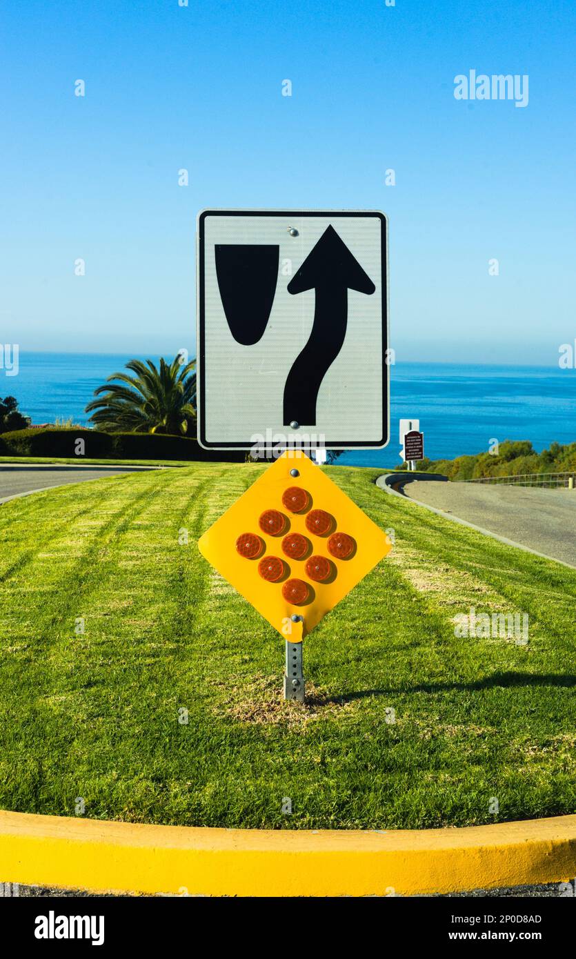 a divided road street sign points up into a cloudless blue sky. High ...