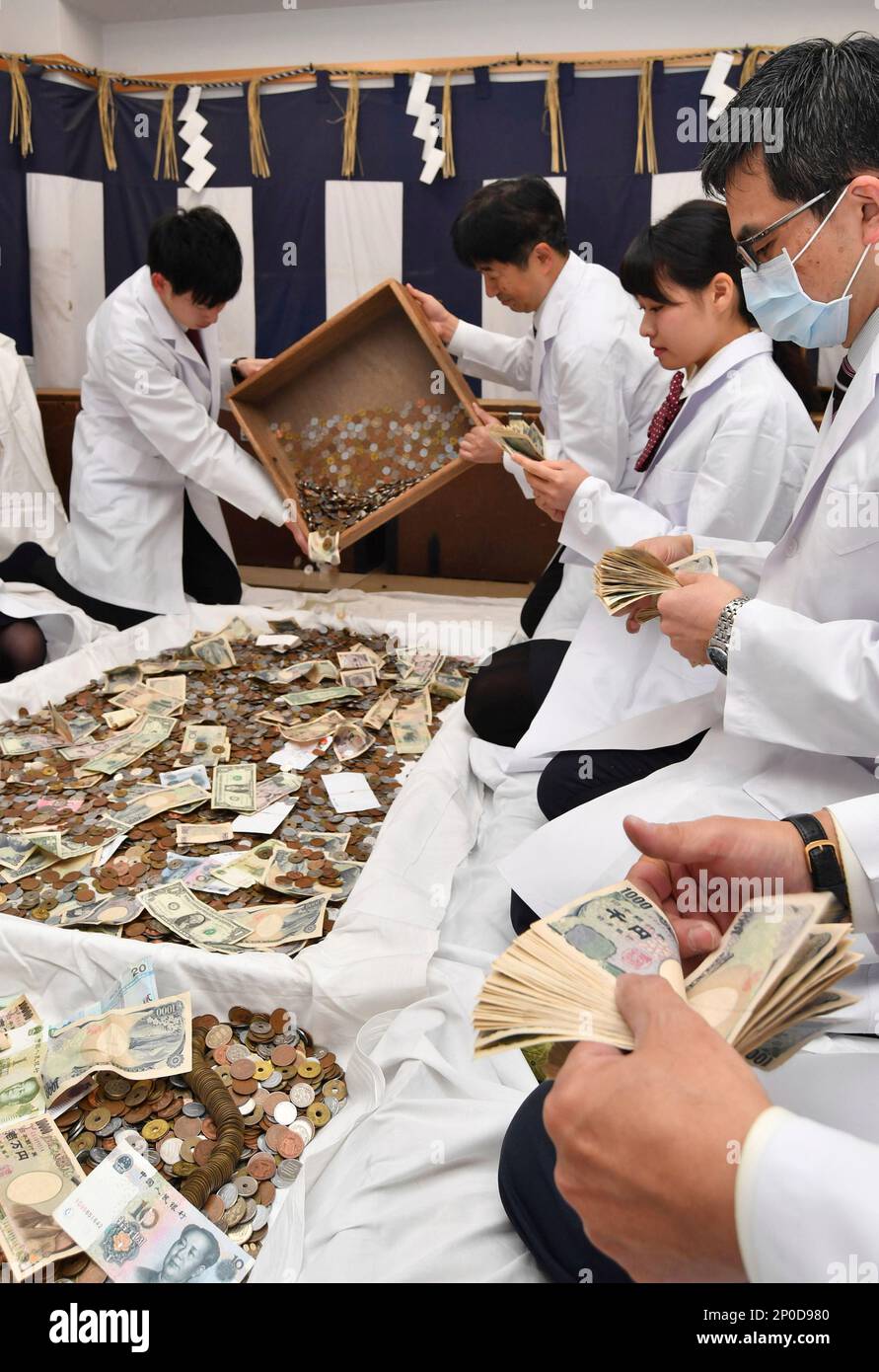 Bank employees, clad in a white robe, start to calculate money offering ...