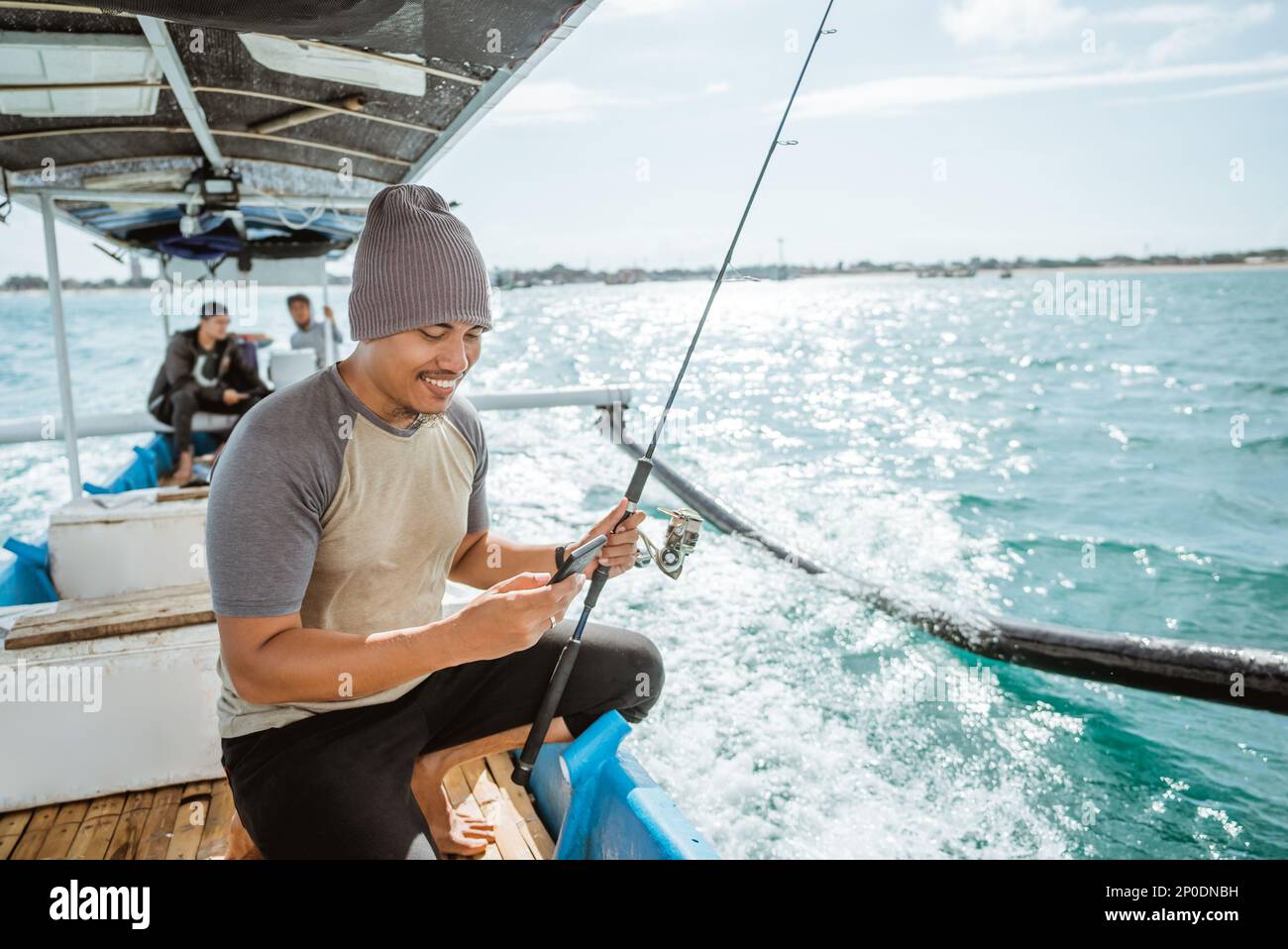 angler using cell phone while fishing with small fishing boat Stock ...