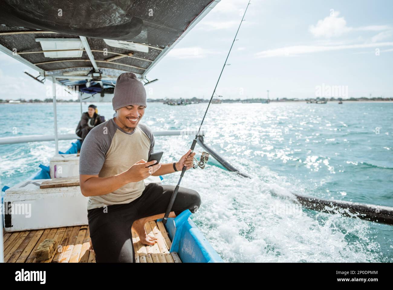 fisherman uses cell phone to send message while fishing Stock Photo - Alamy