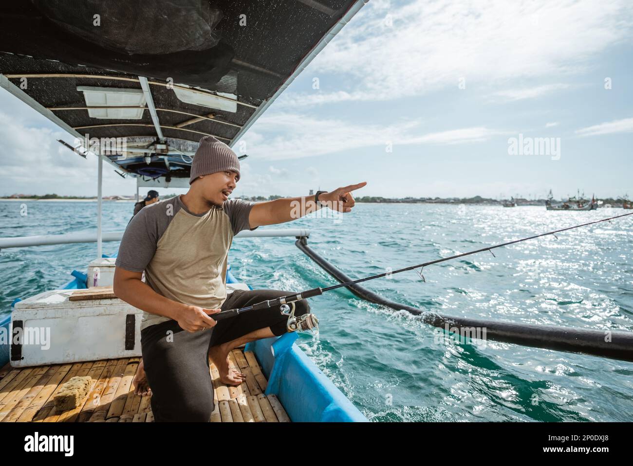 angler with finger pointing while holding rod over small boat Stock ...