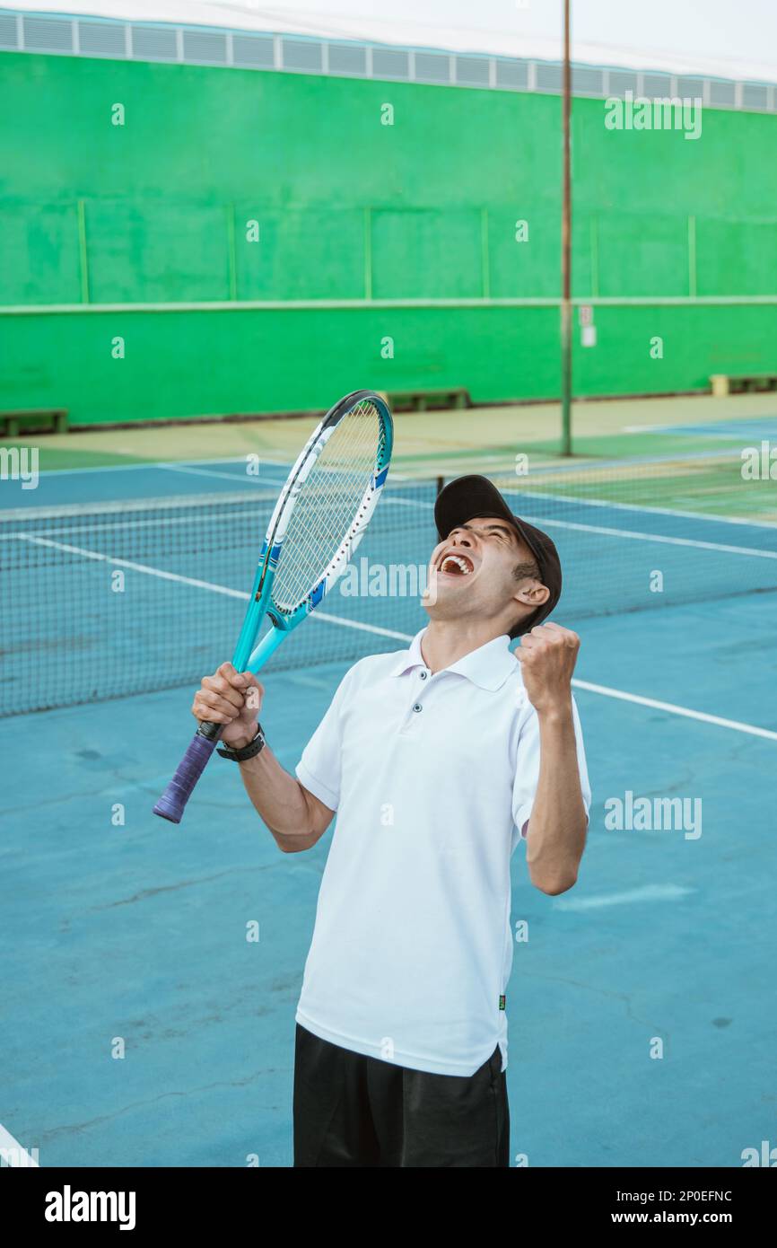 male athlete shouting happily celebrating victory by carrying racket ...