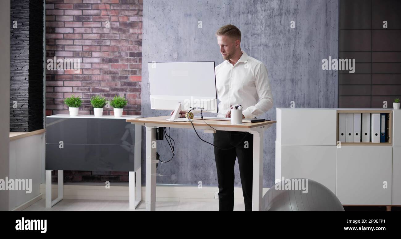 Man Using Adjustable Height Standing Desk In Office For Good Posture ...