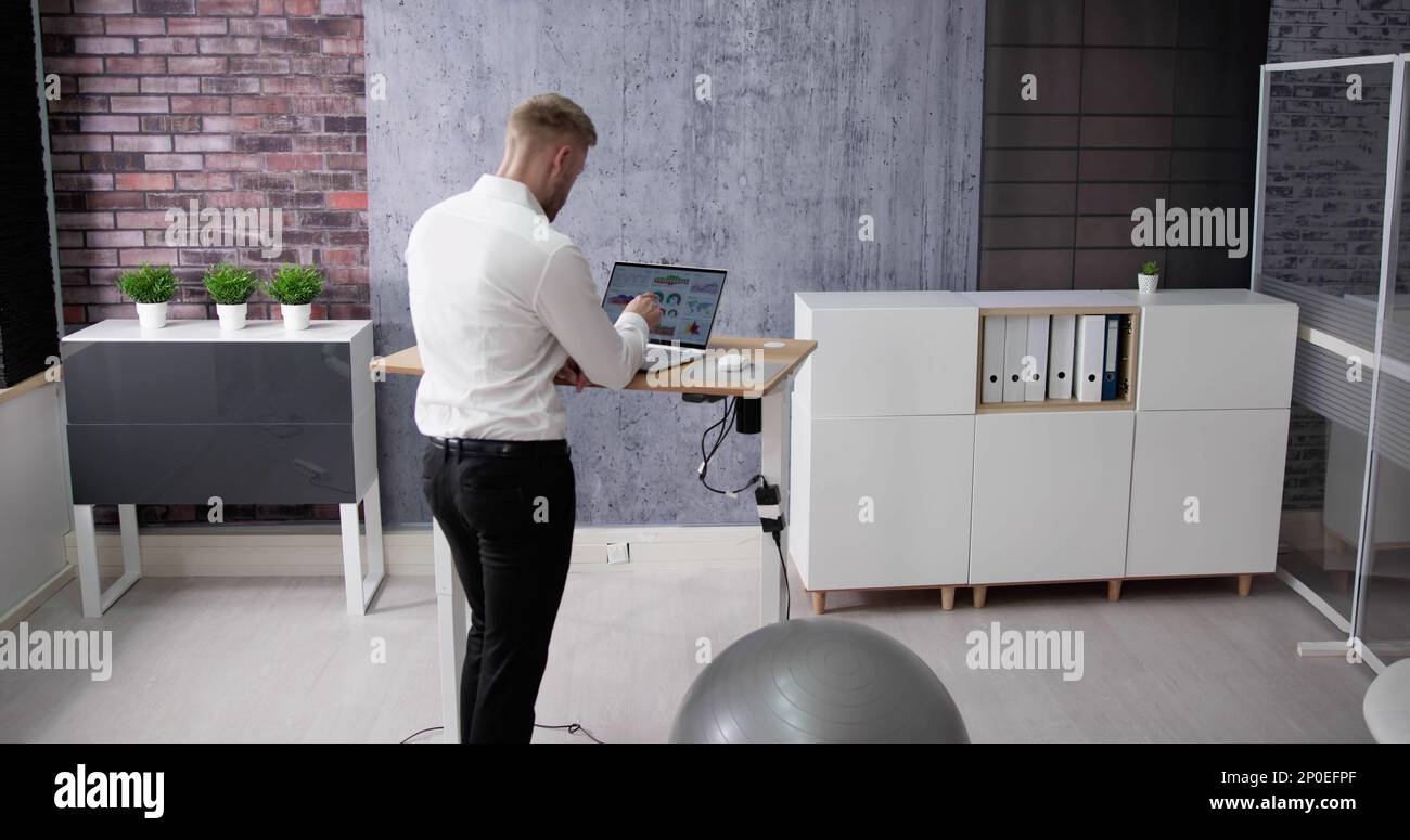 Man Using Adjustable Height Standing Desk In Office For Good Posture ...