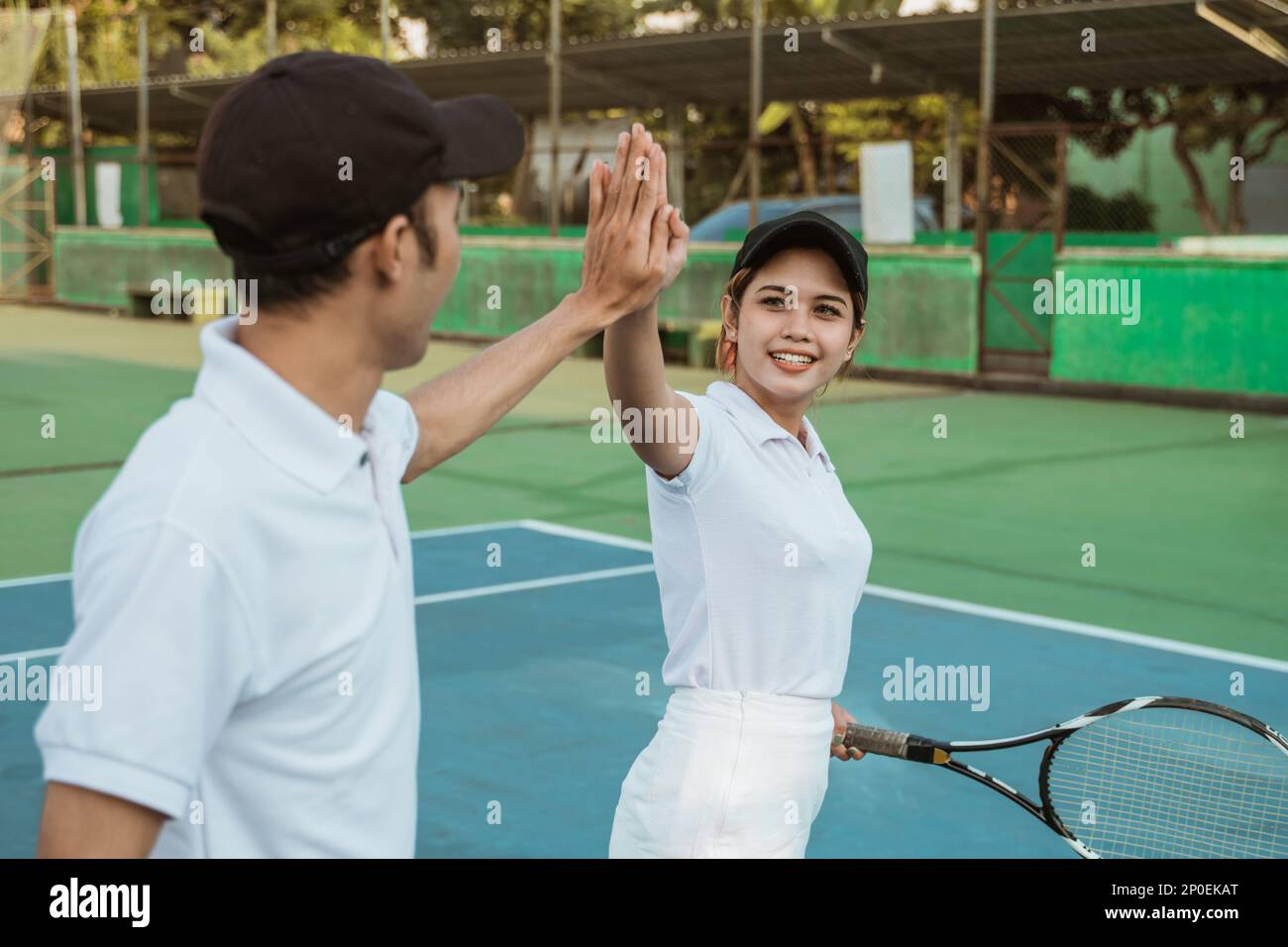 Mixed doubles tennis athletes high-five each other celebrating victory ...