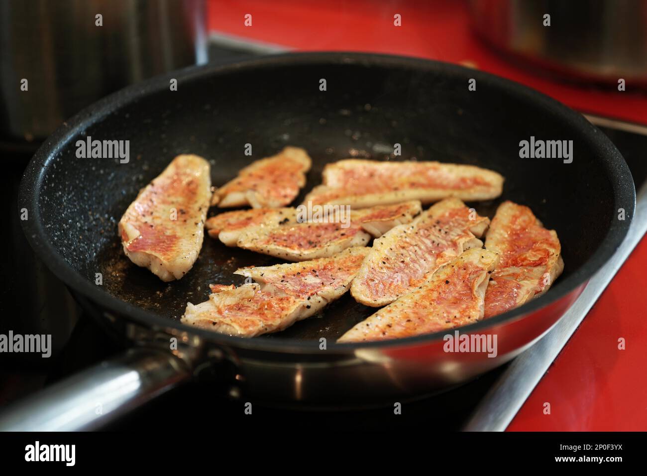 preparing roasted red mullet fish fillets in frying pan. selective ...