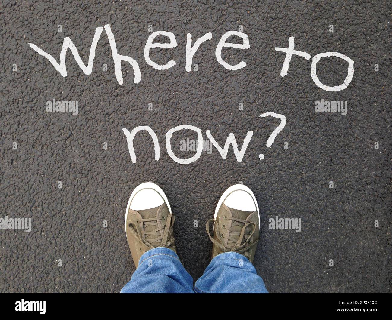 feet standing on road with where to now question written on asphalt ...
