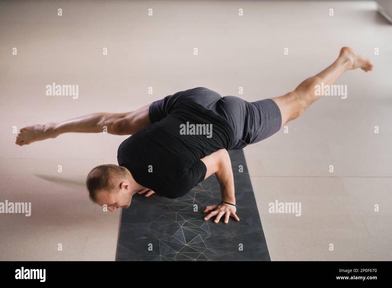An athletically built man does yoga in the gym on a mat Stock Photo - Alamy