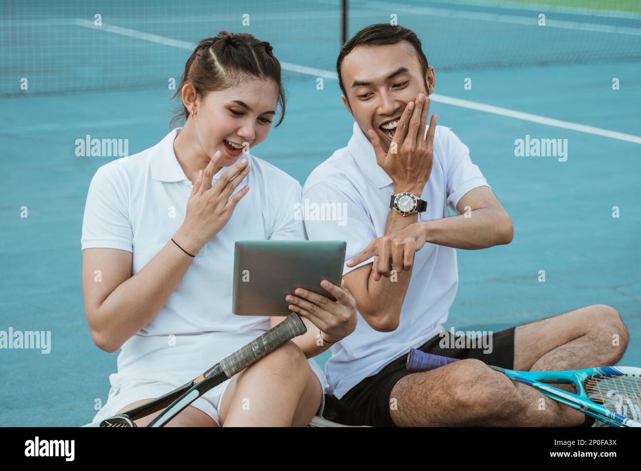 doubles tennis players laughing while sitting looking at tablet ...