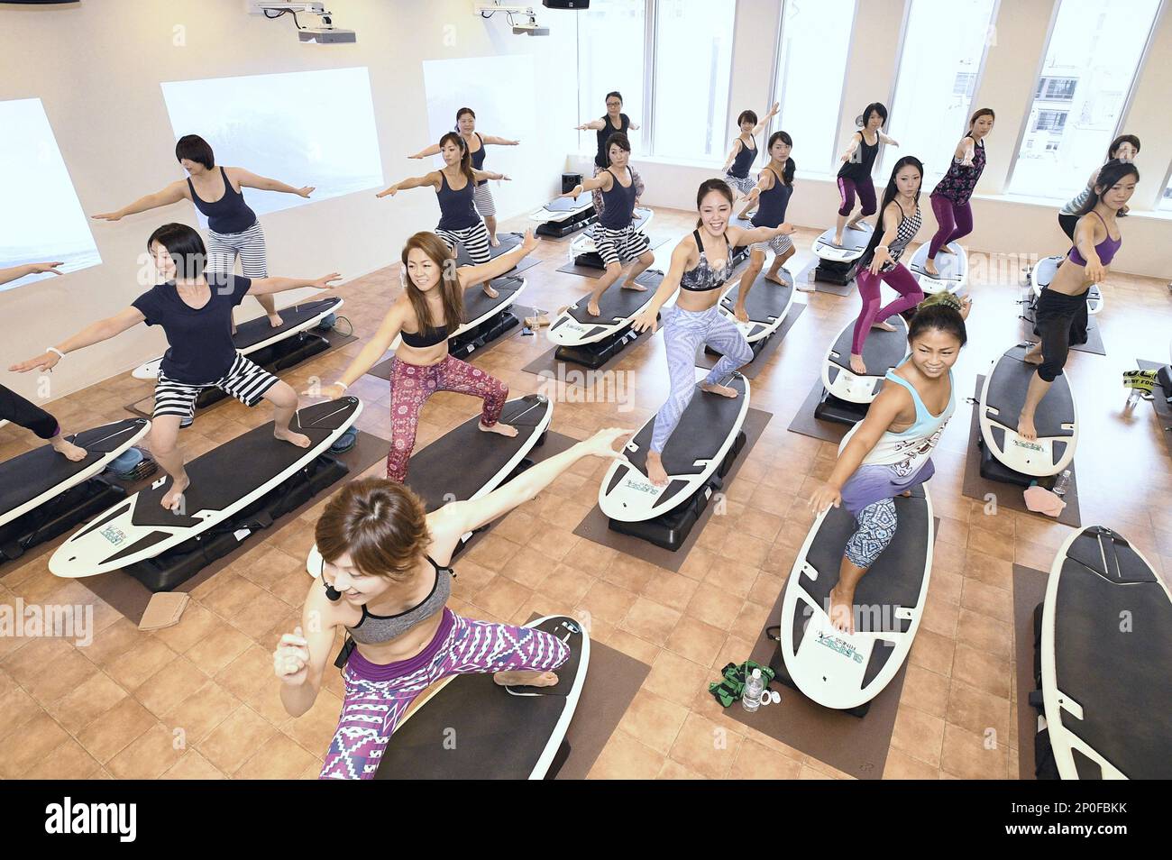 22 women work out on surfboards to up-tempo music in a room as hot as a ...