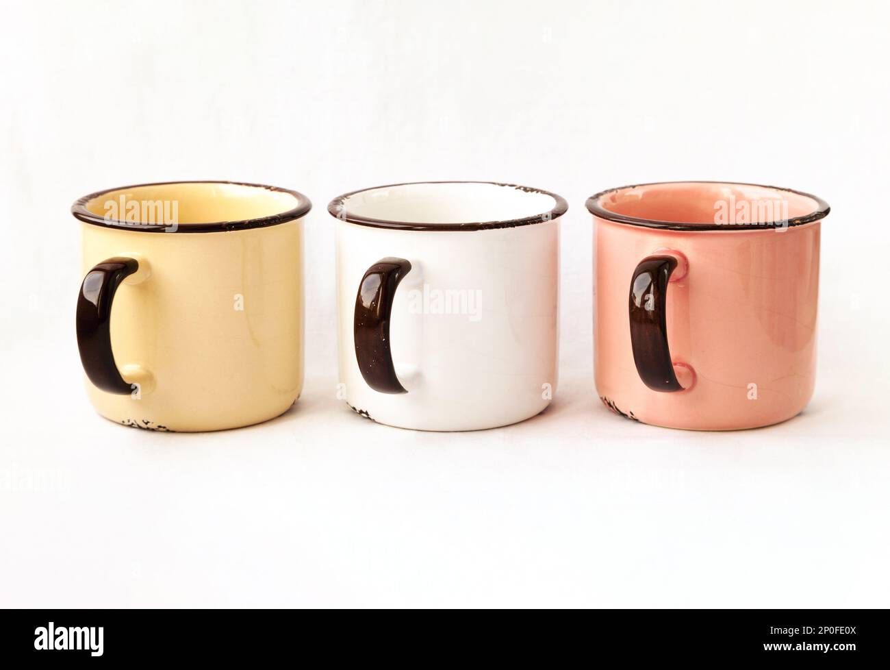 Three old retro metal tea cups in a row isolated. Some yellow, white ...