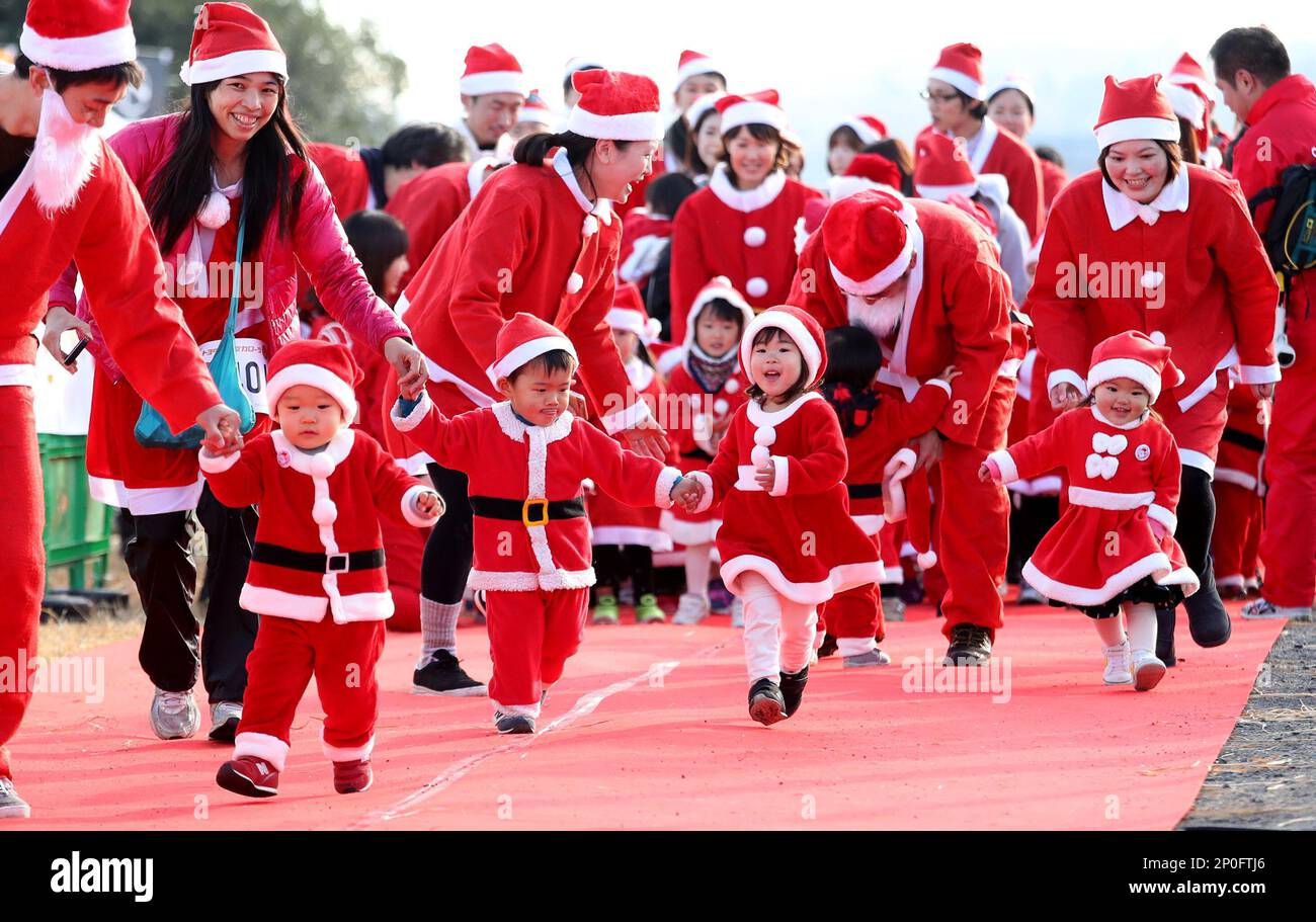 Kids clad in Santa Claus costume run on the way of Tama River bed in ...