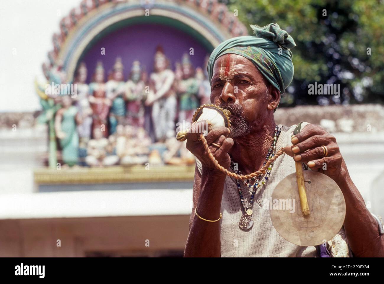 Sadhu blowing conch standing infornt of Nataraja temple, Perur near ...