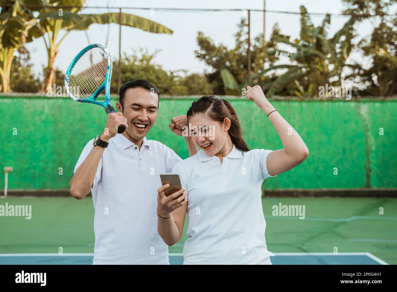 excited mixed doubles athletes using cell phones together Stock Photo ...