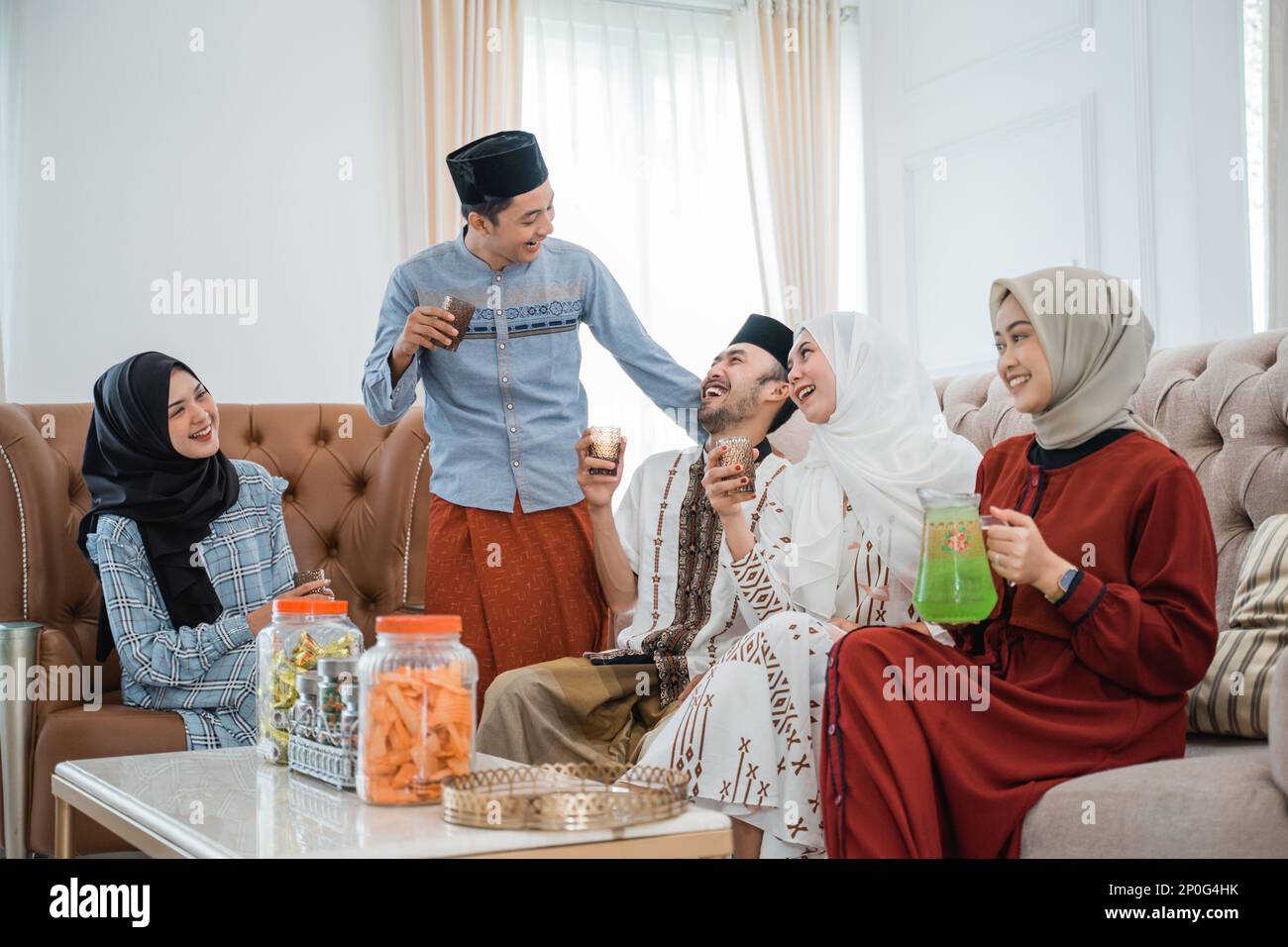 Muslim friends chatting together celebrating Eid by drinking and eating ...