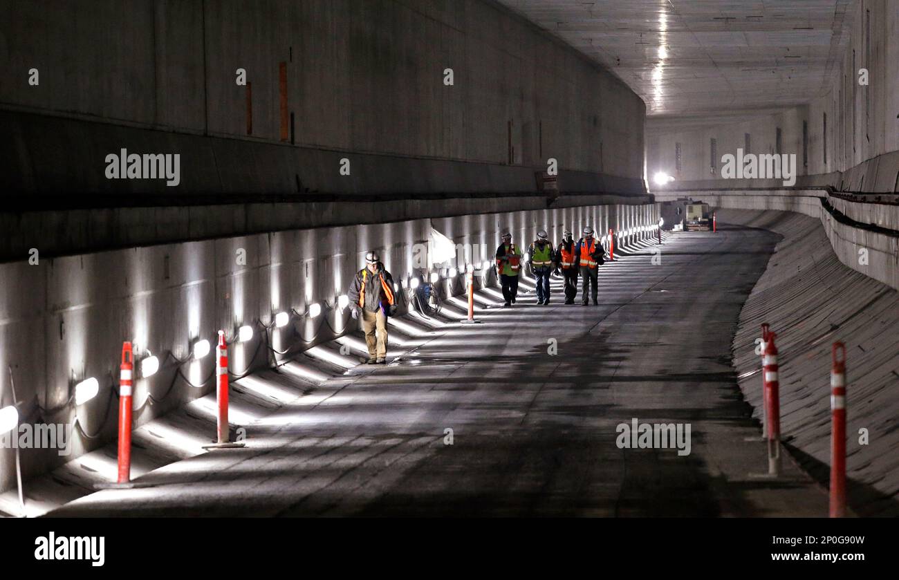 Workers walk inside the State Route 99 tunnel and below a completed ...